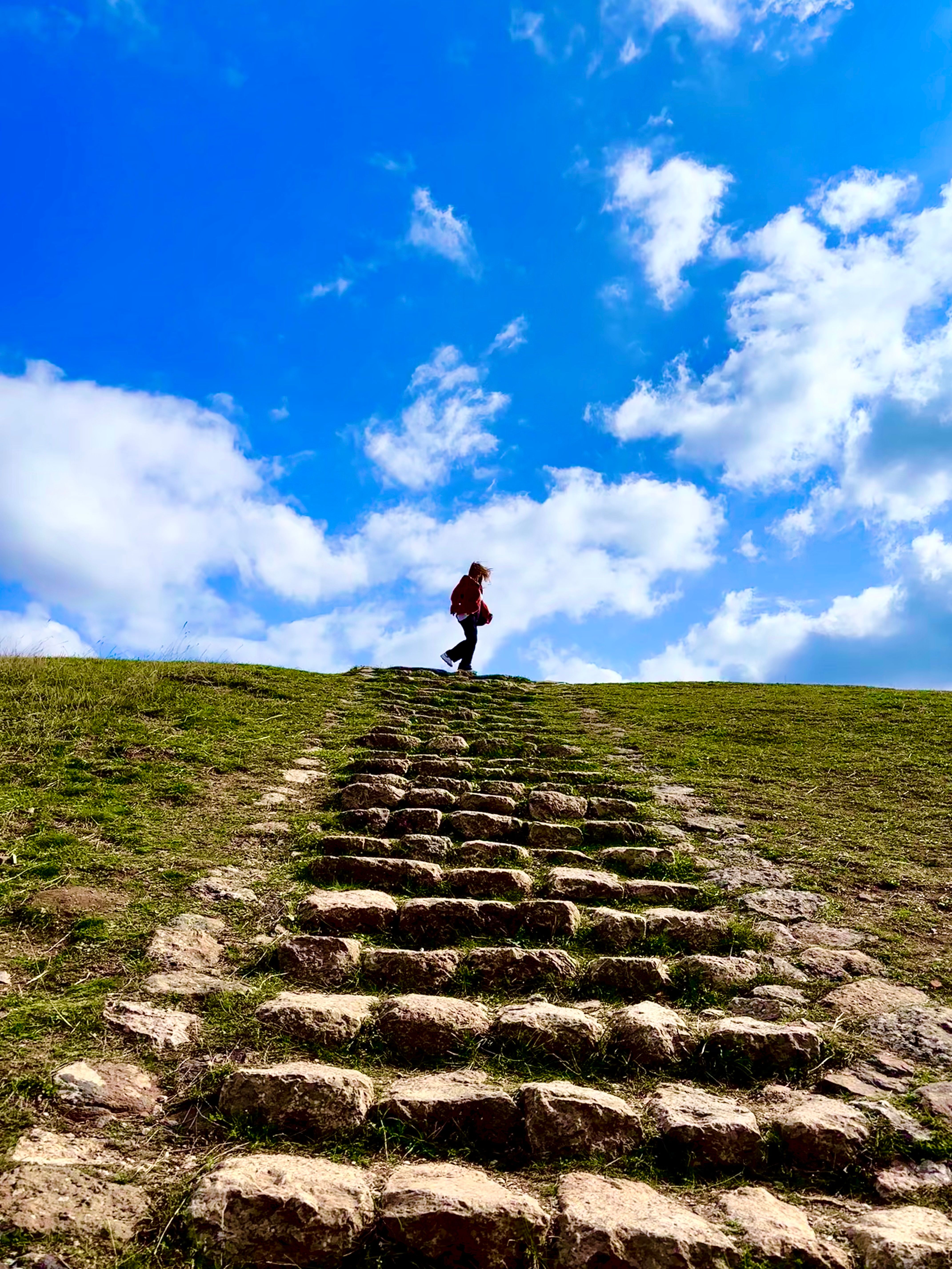 Hiker Ascending Stone Steps Under Blue Sky · Free Stock Photo