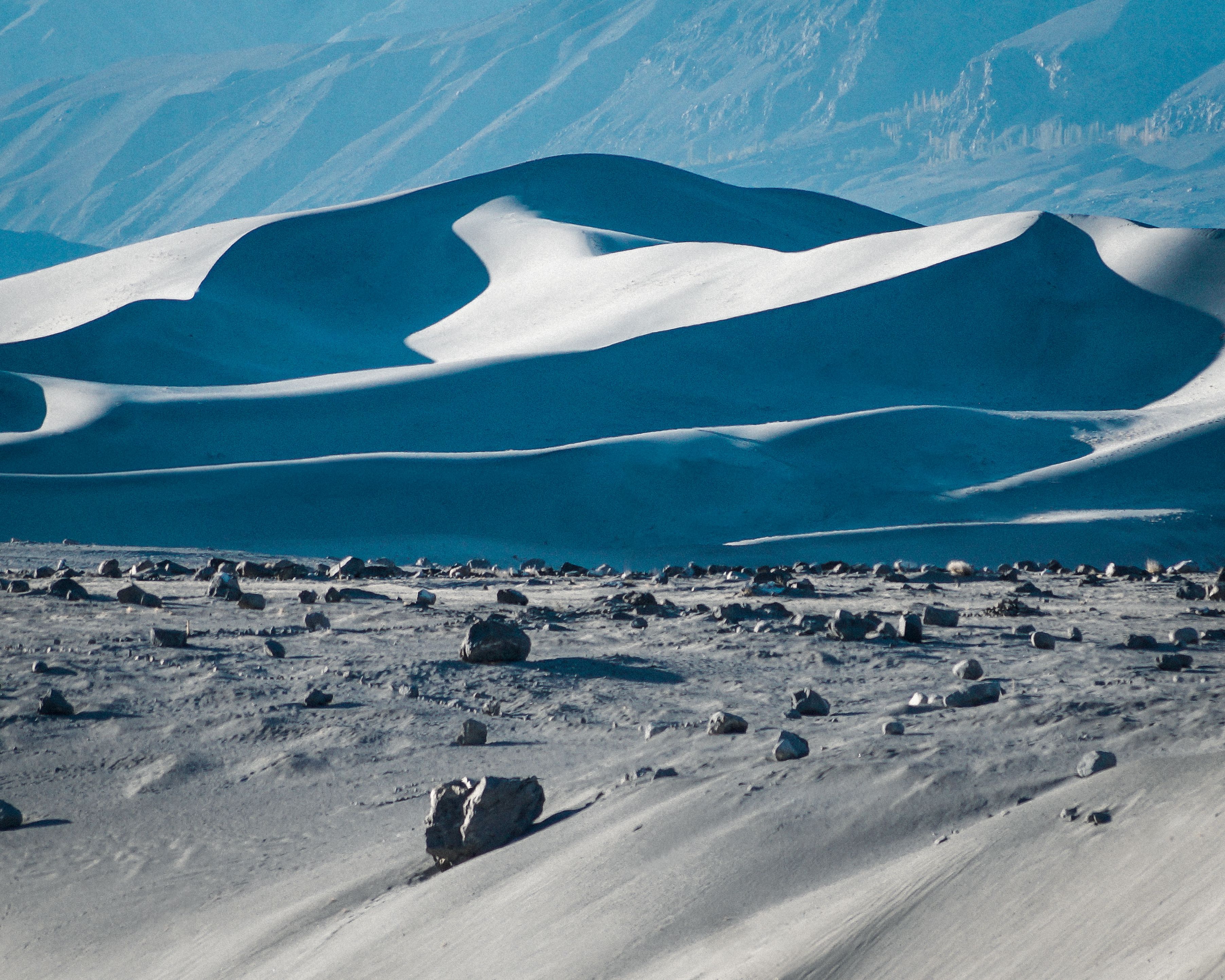 Dramatic Blue Dunes Under Mountainous Backdrop · Free Stock Photo
