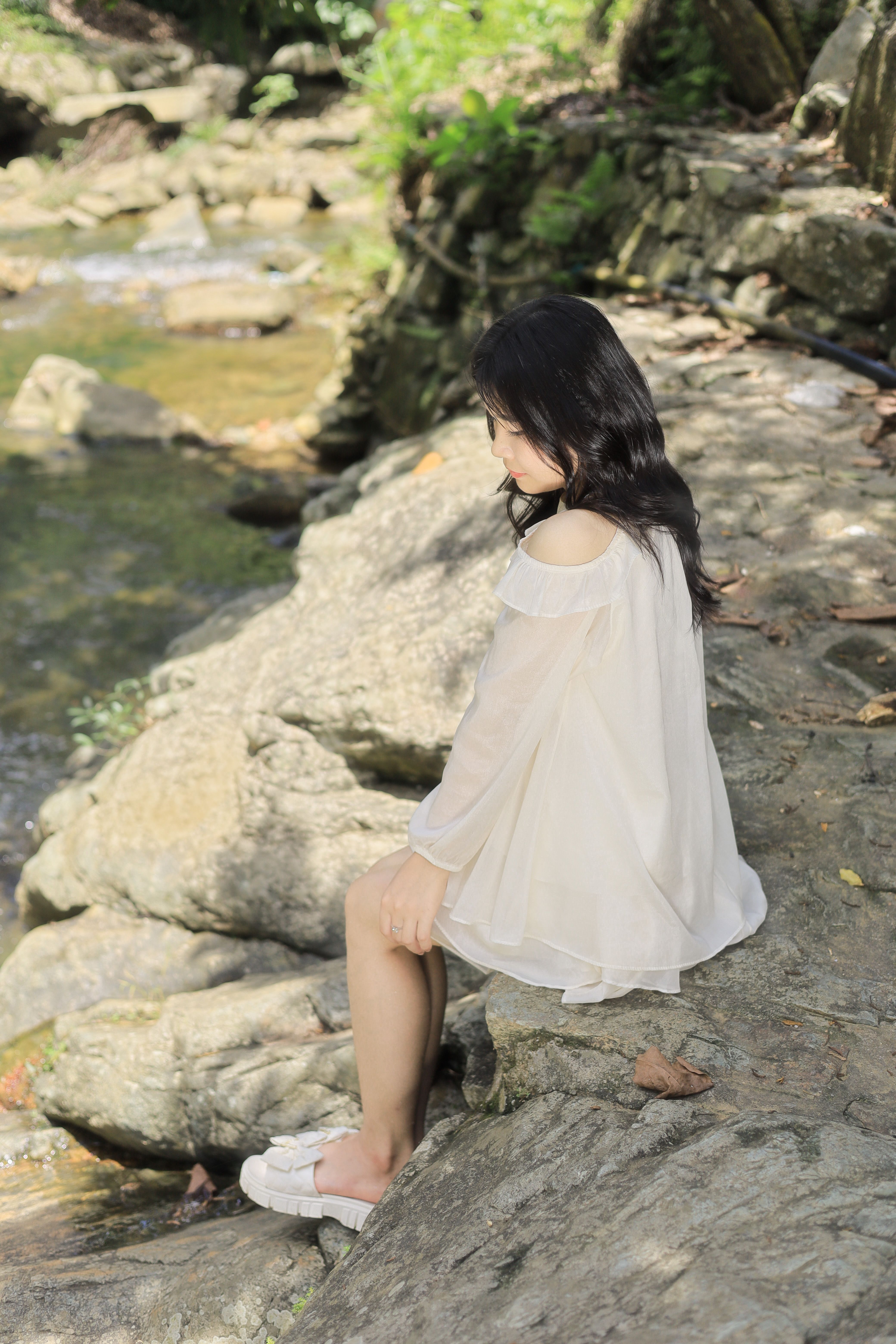 Young Woman Sitting on Rocks by Stream · Free Stock Photo
