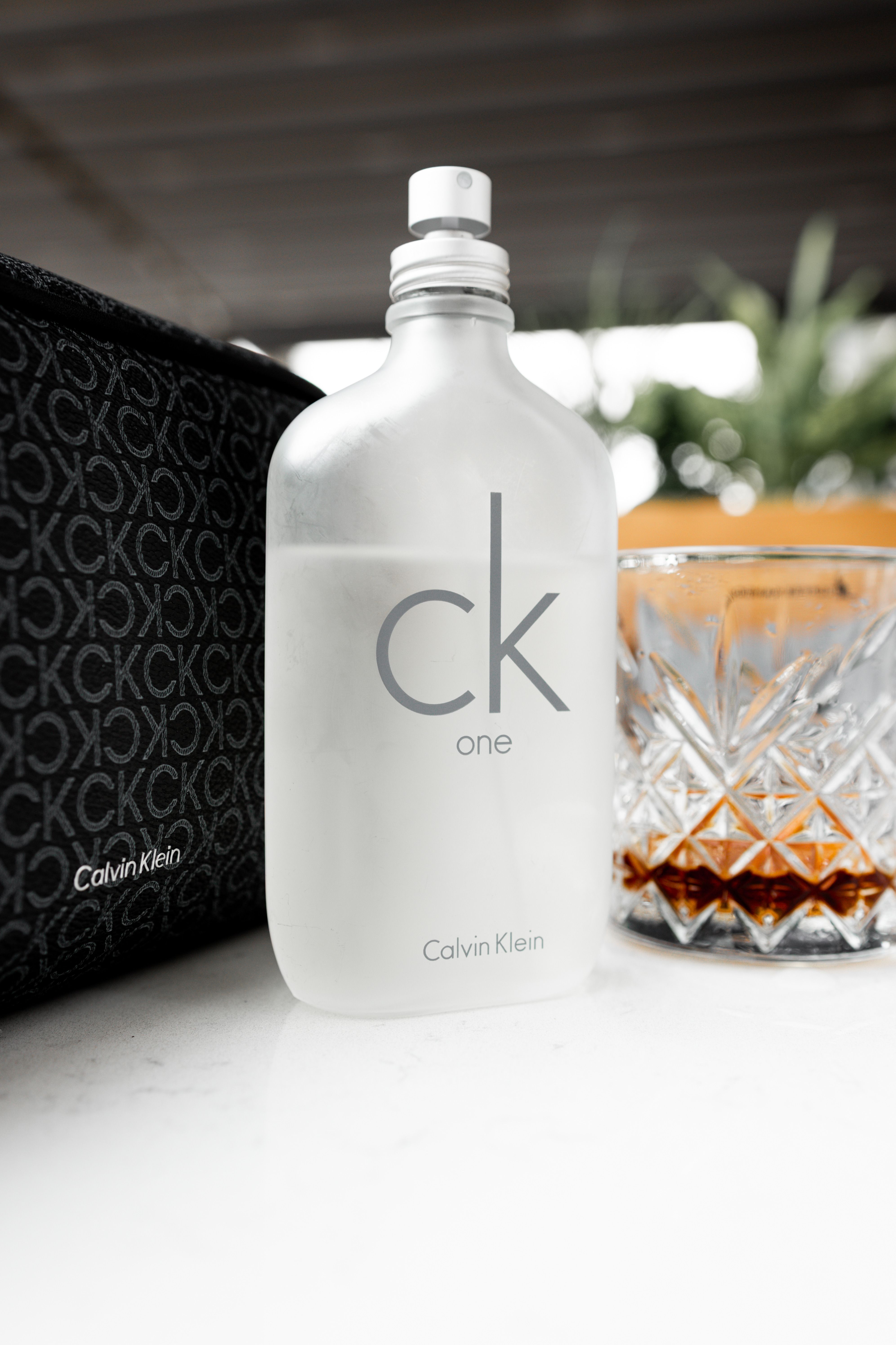 Calvin Klein Fragrance and Glass on Outdoor Table · Free Stock Photo