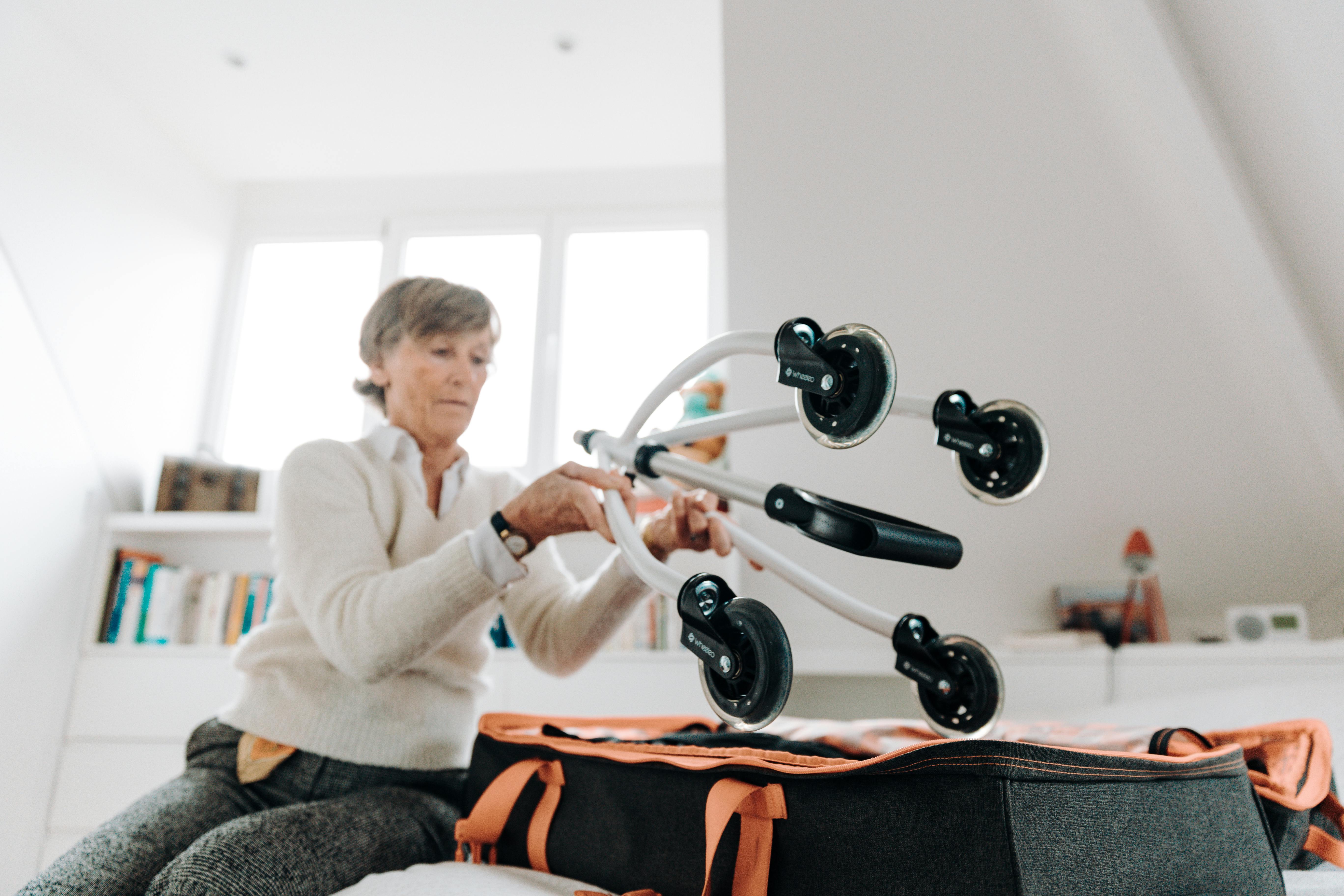 Senior woman packing a rollator in a suitcase · Free Stock Photo