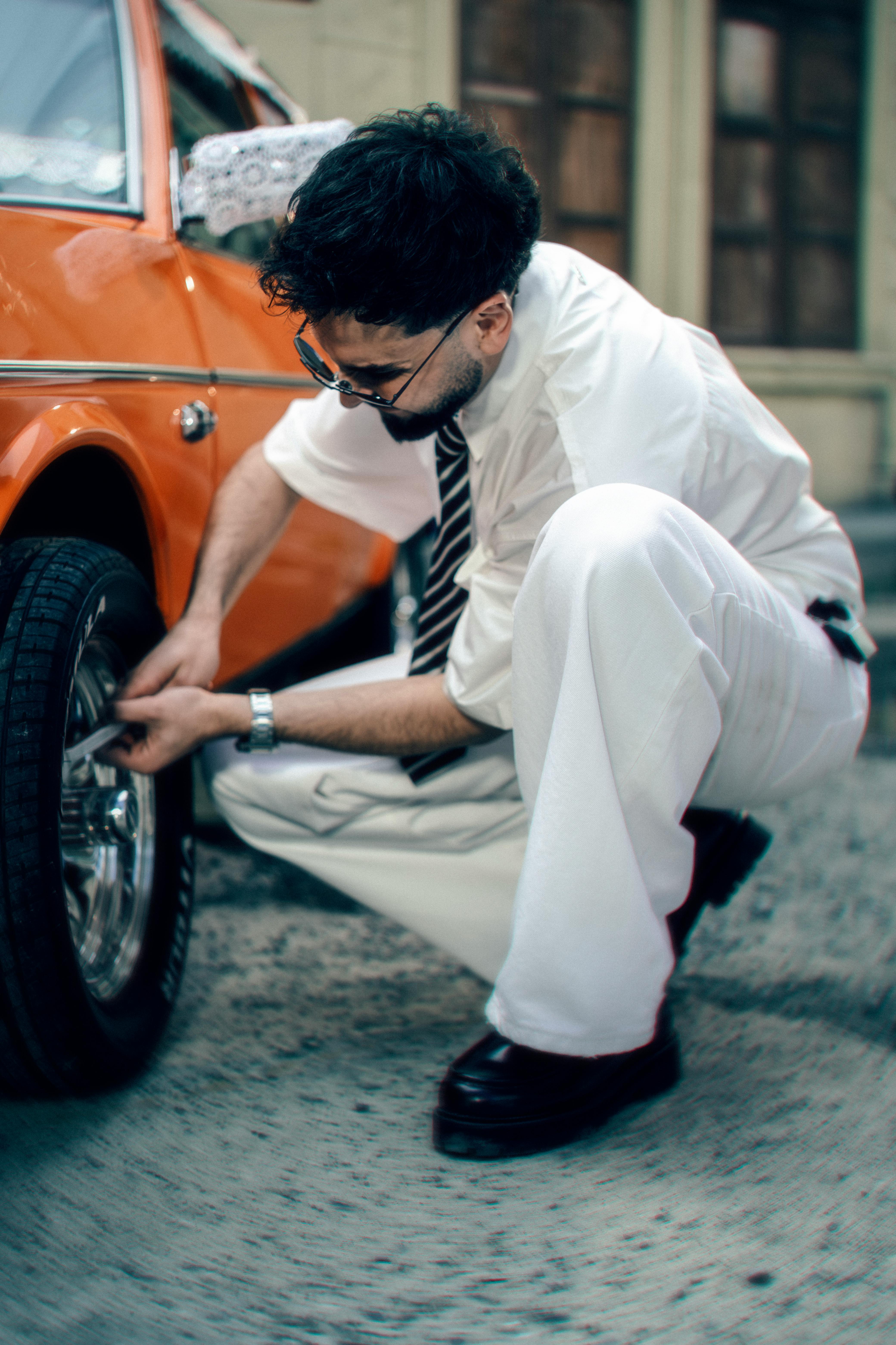 Man Fixing Car Tire on City Street · Free Stock Photo