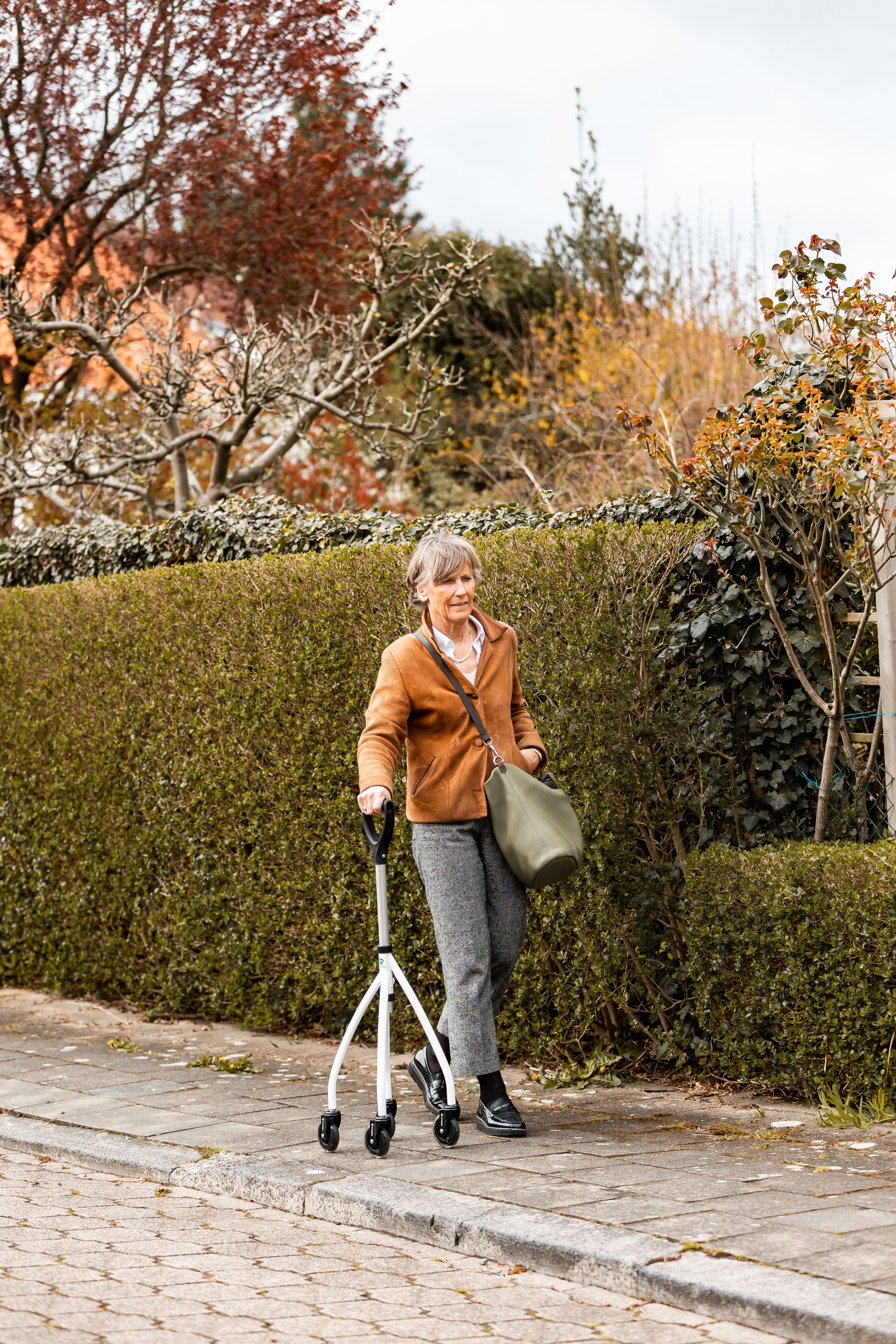 Senior Woman Strolling with Rollator on Autumn Street · Free Stock Photo