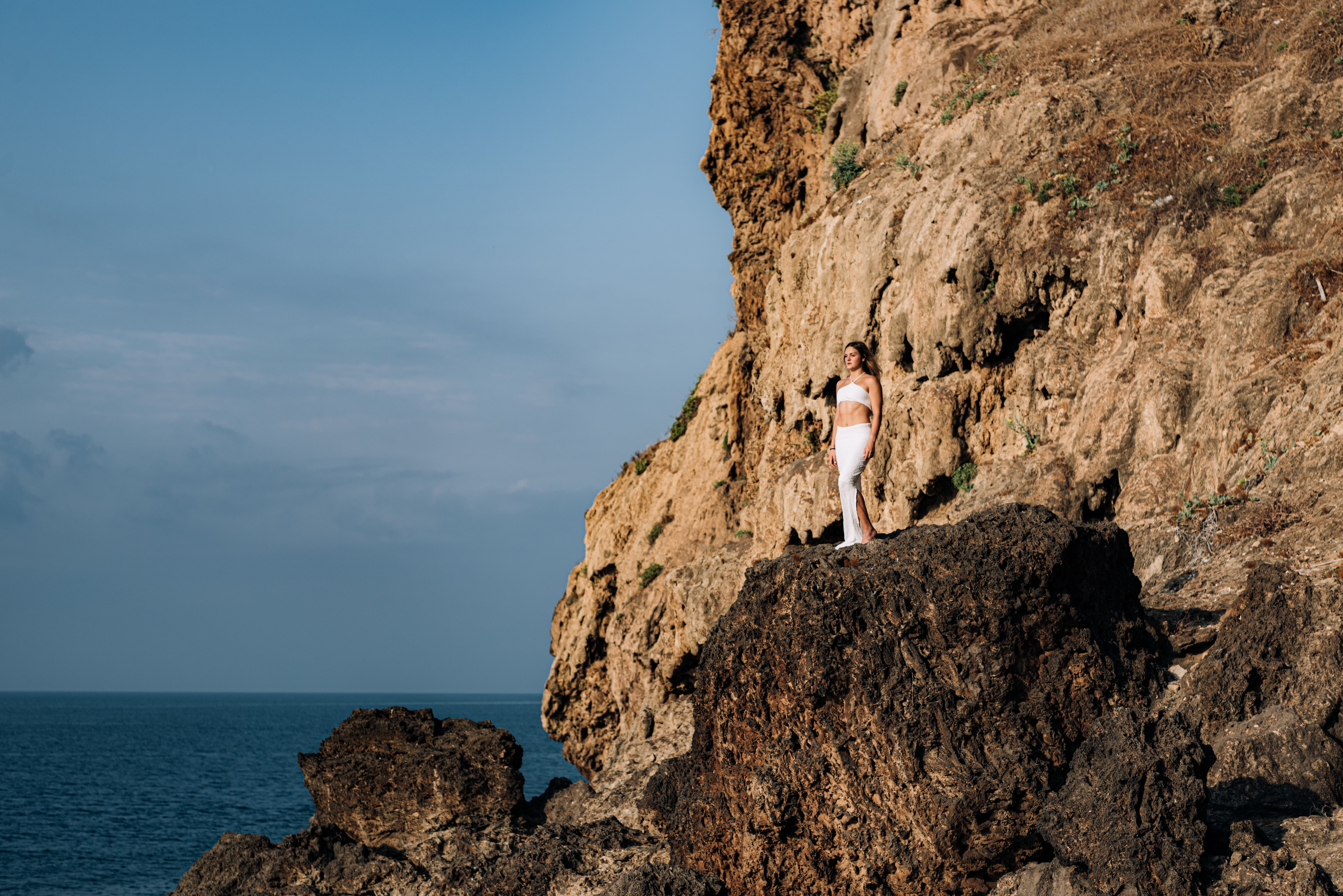 Woman Standing on Rocky Cliff Overlooking Ocean · Free Stock Photo