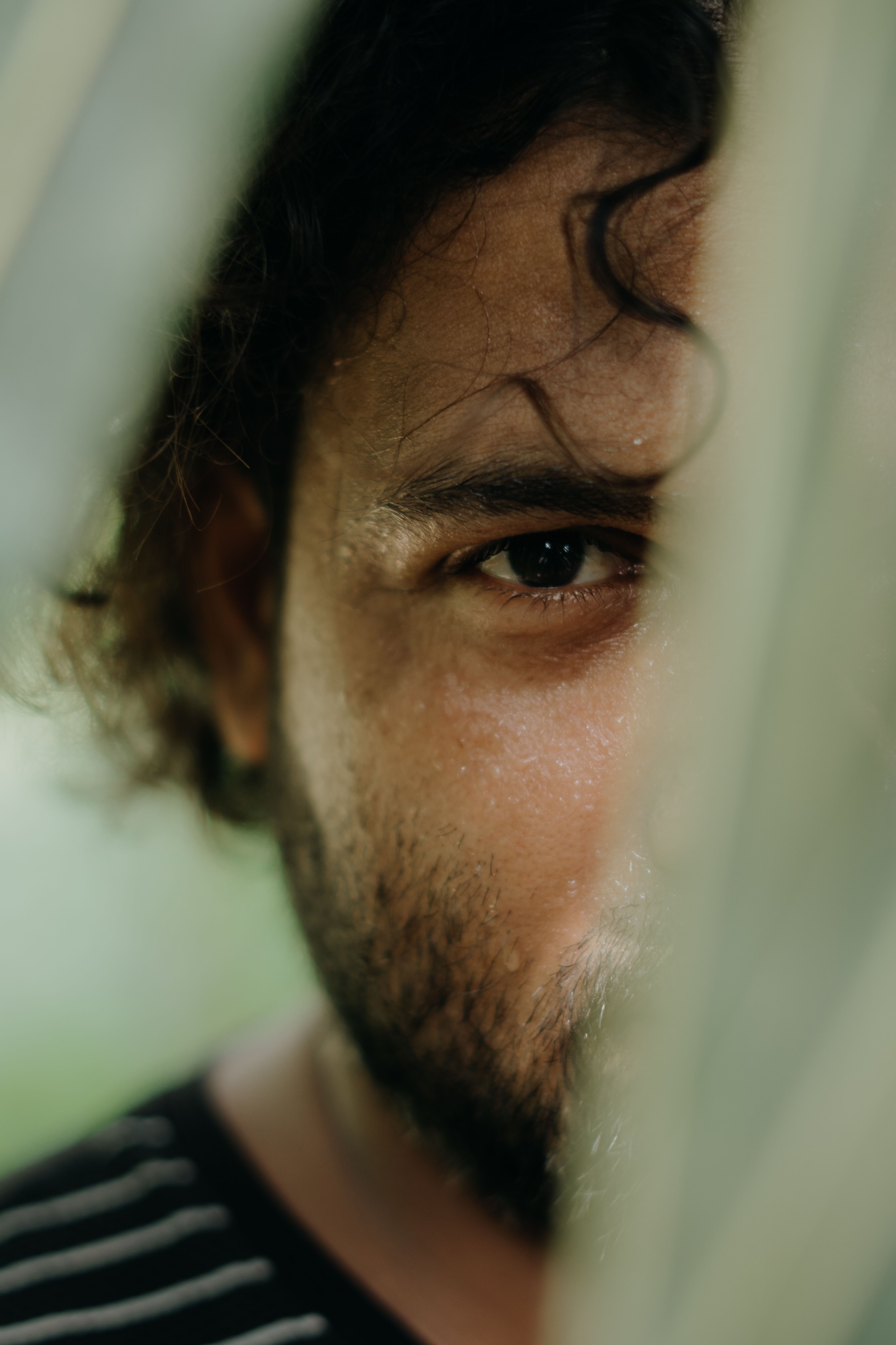 Close-up of Man's Face Partially Obscured by Leaf · Free Stock Photo