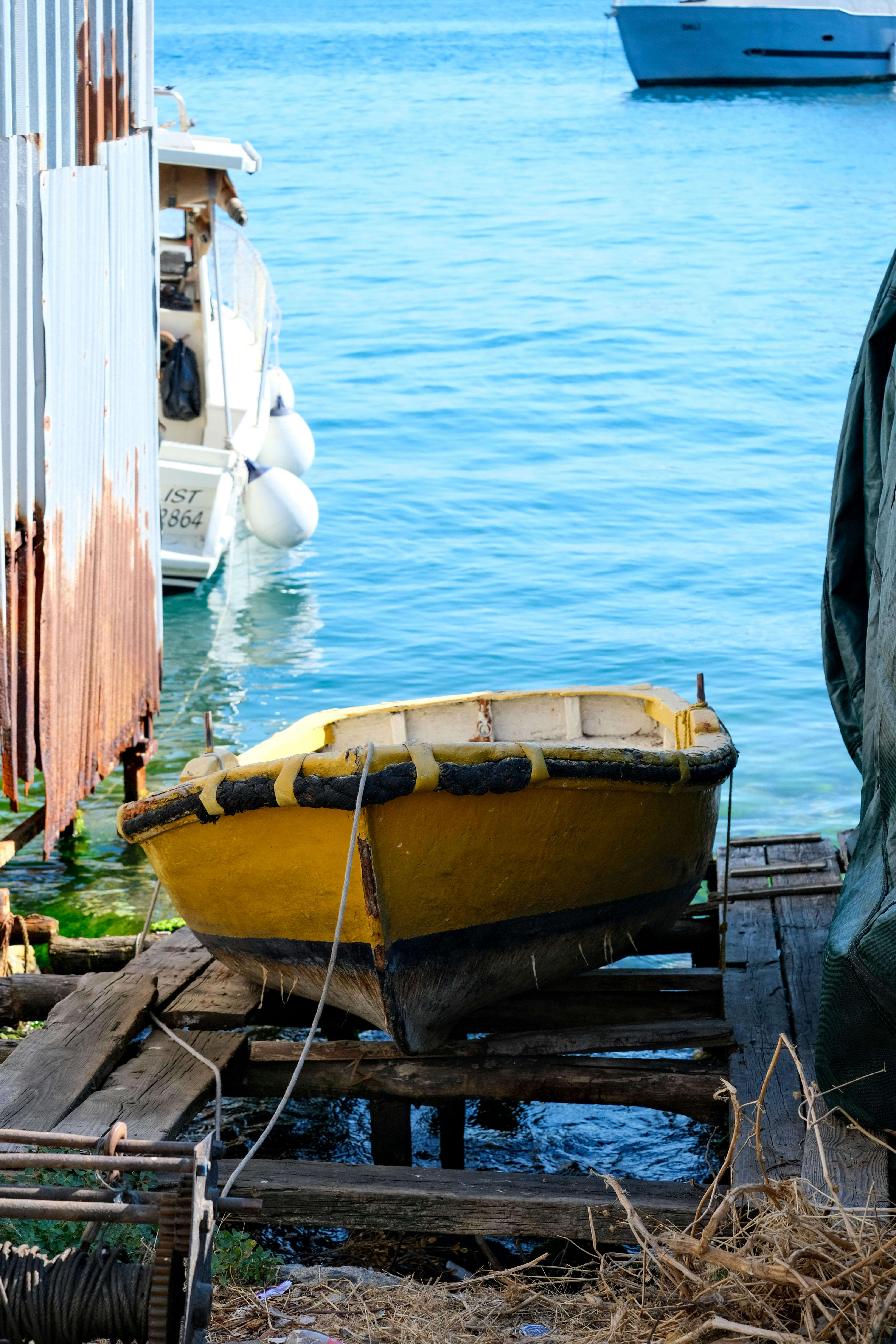 Yellow Rowboat on a Weathered Dock by Blue Water · Free Stock Photo