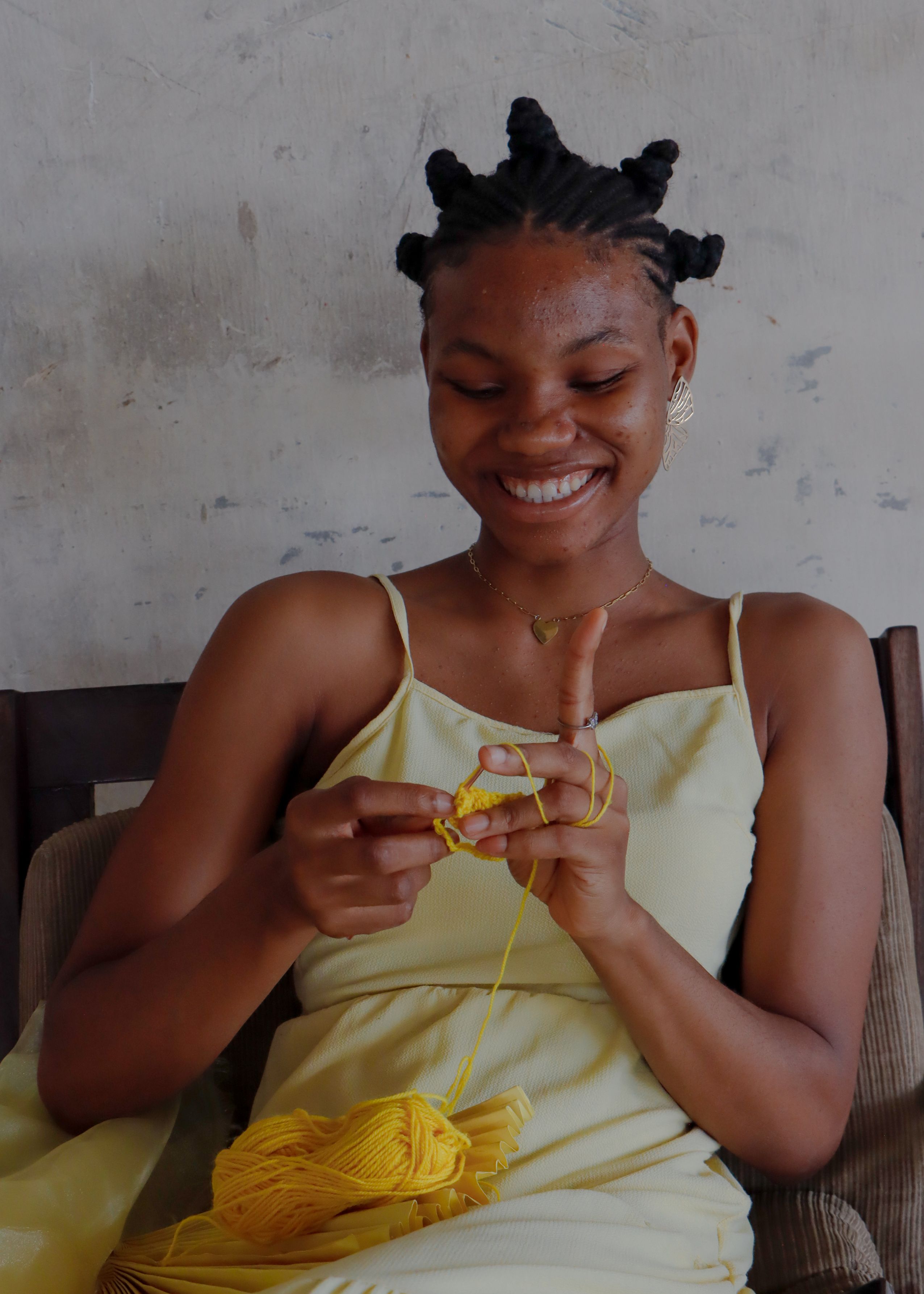 Smiling Woman Crocheting in Yellow Dress · Free Stock Photo