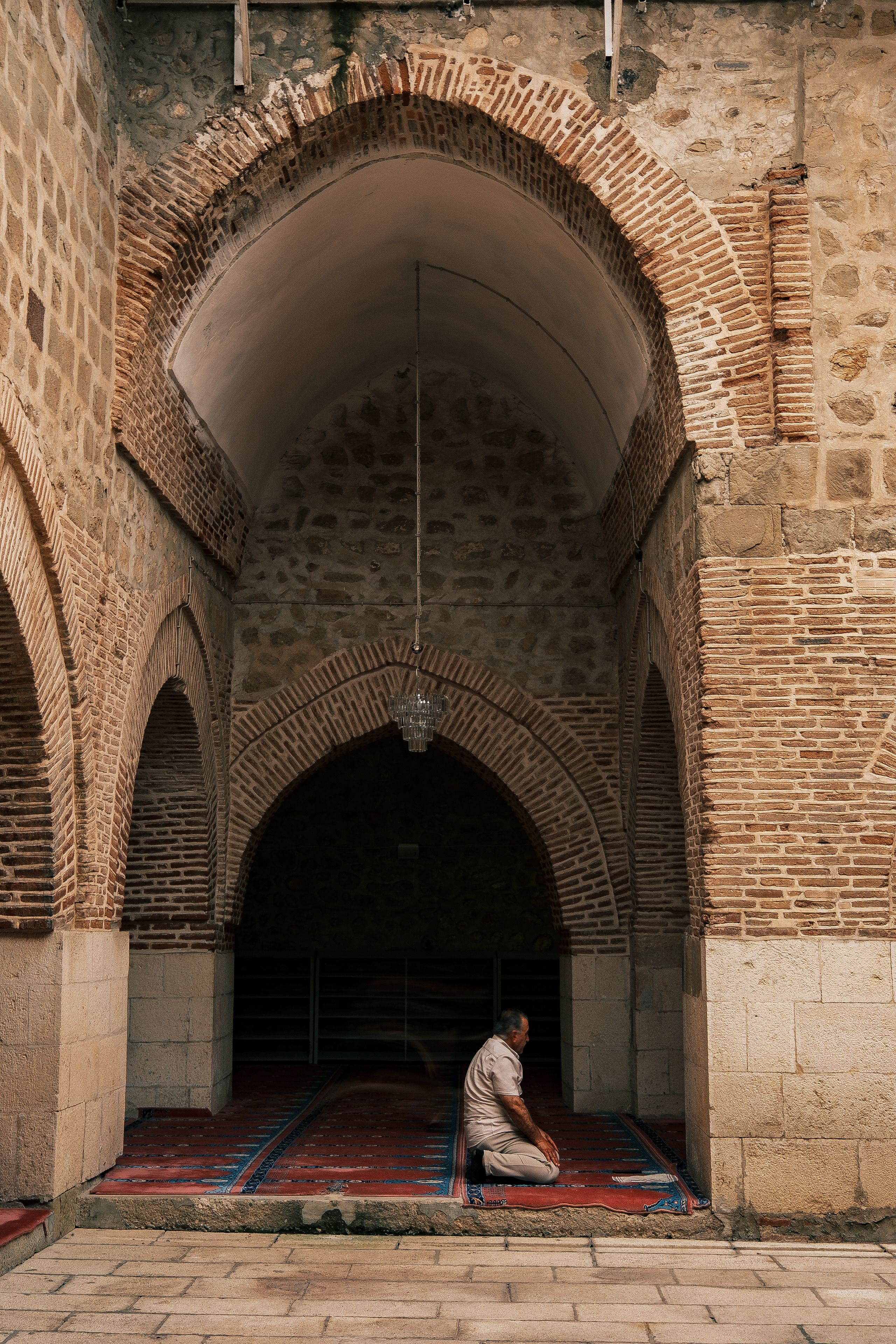 Man Praying Inside Historical Mosque with Arches · Free Stock Photo