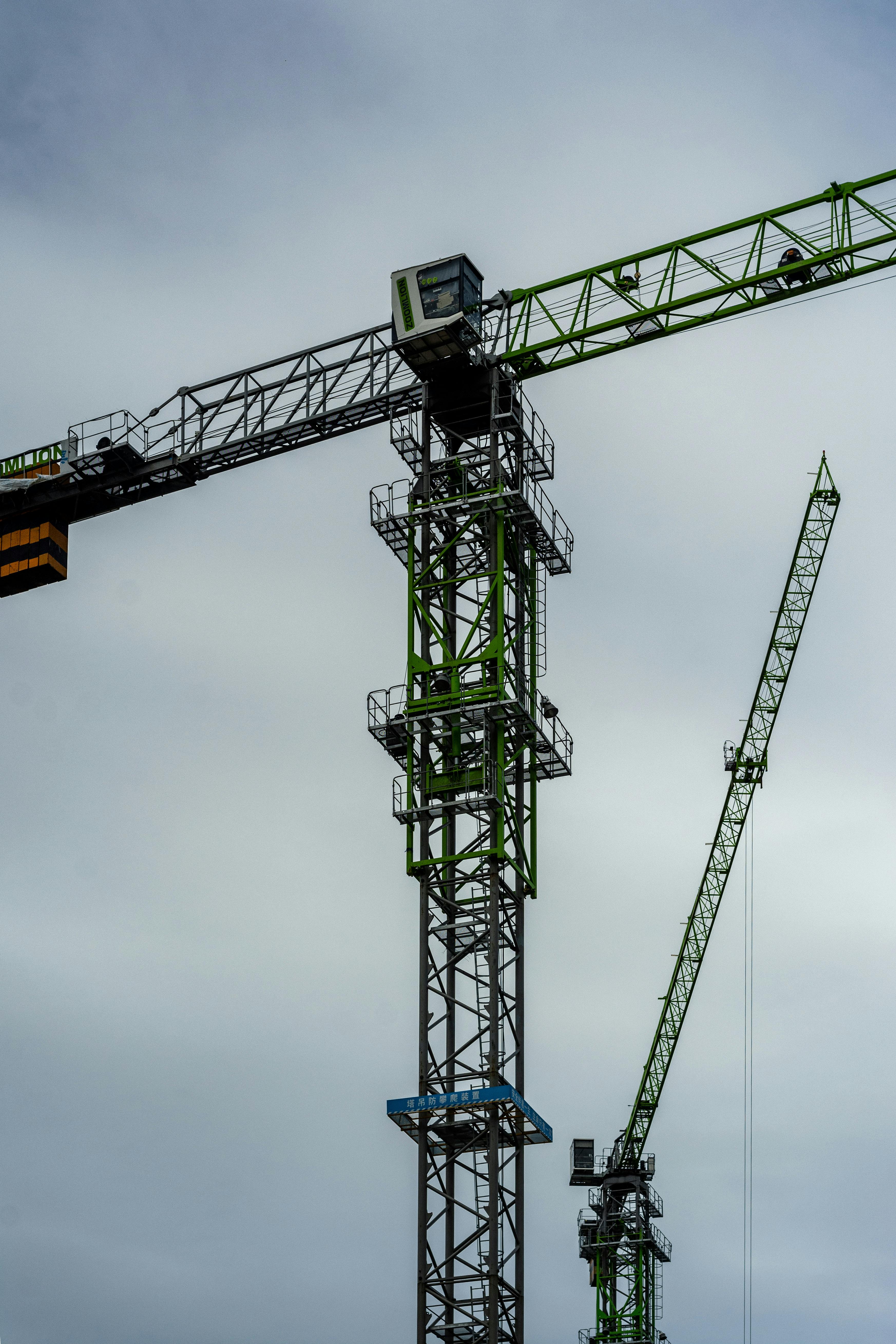 Tall Construction Cranes Against a Cloudy Sky · Free Stock Photo