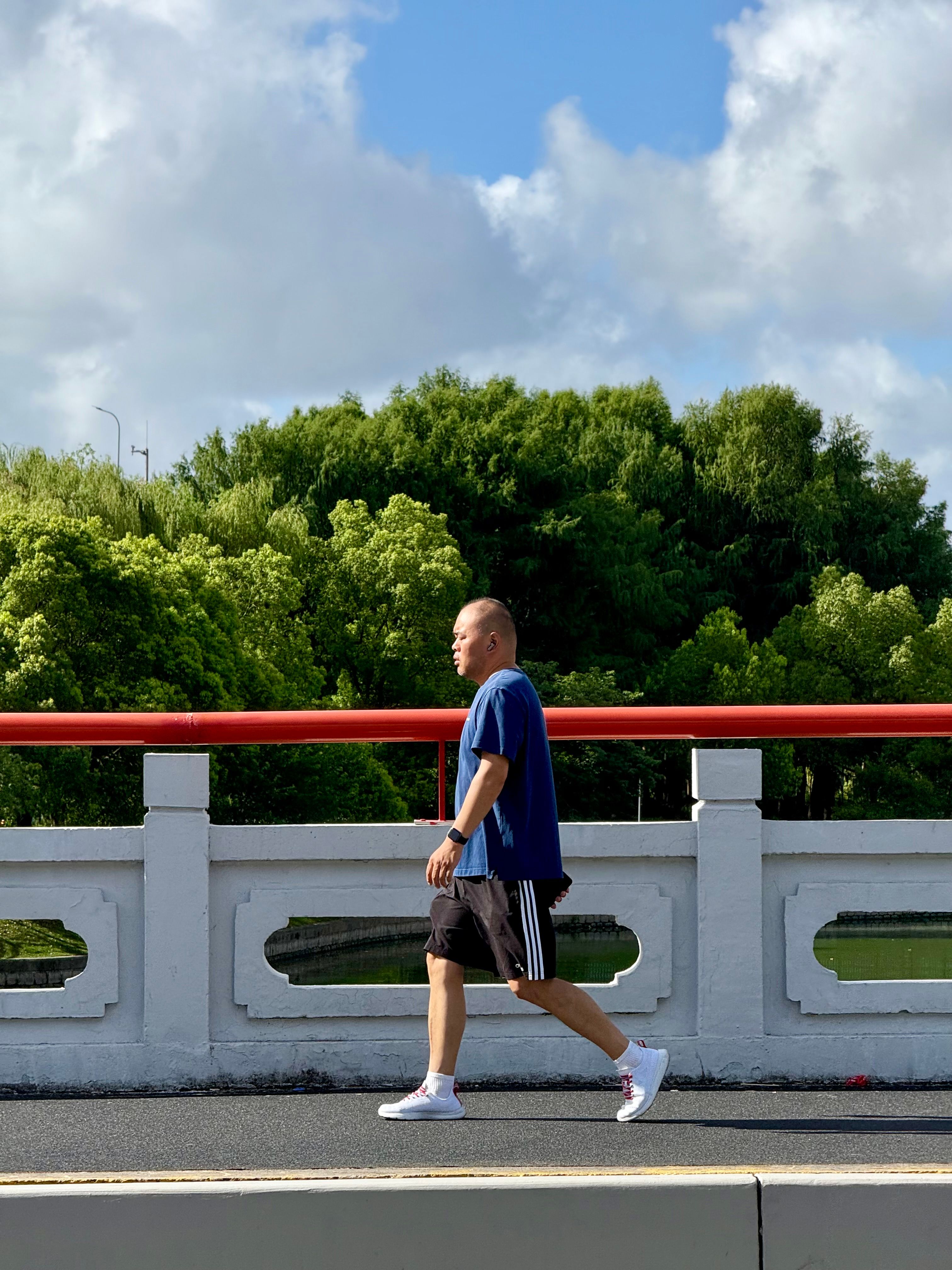 Man Walking on Bridge in Sunny Urban Setting · Free Stock Photo