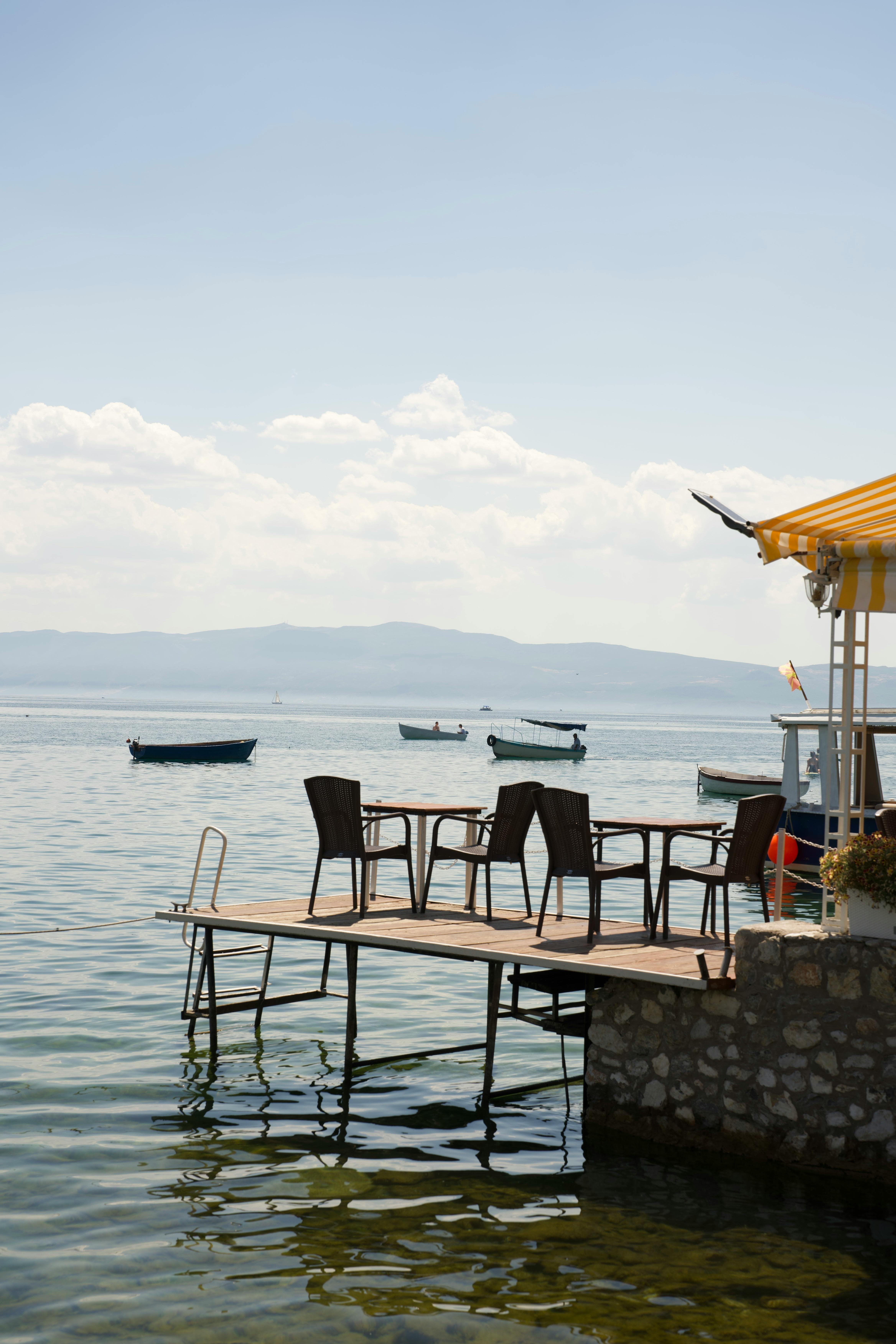 Charming Lakeside Seating with Boats on Water · Free Stock Photo