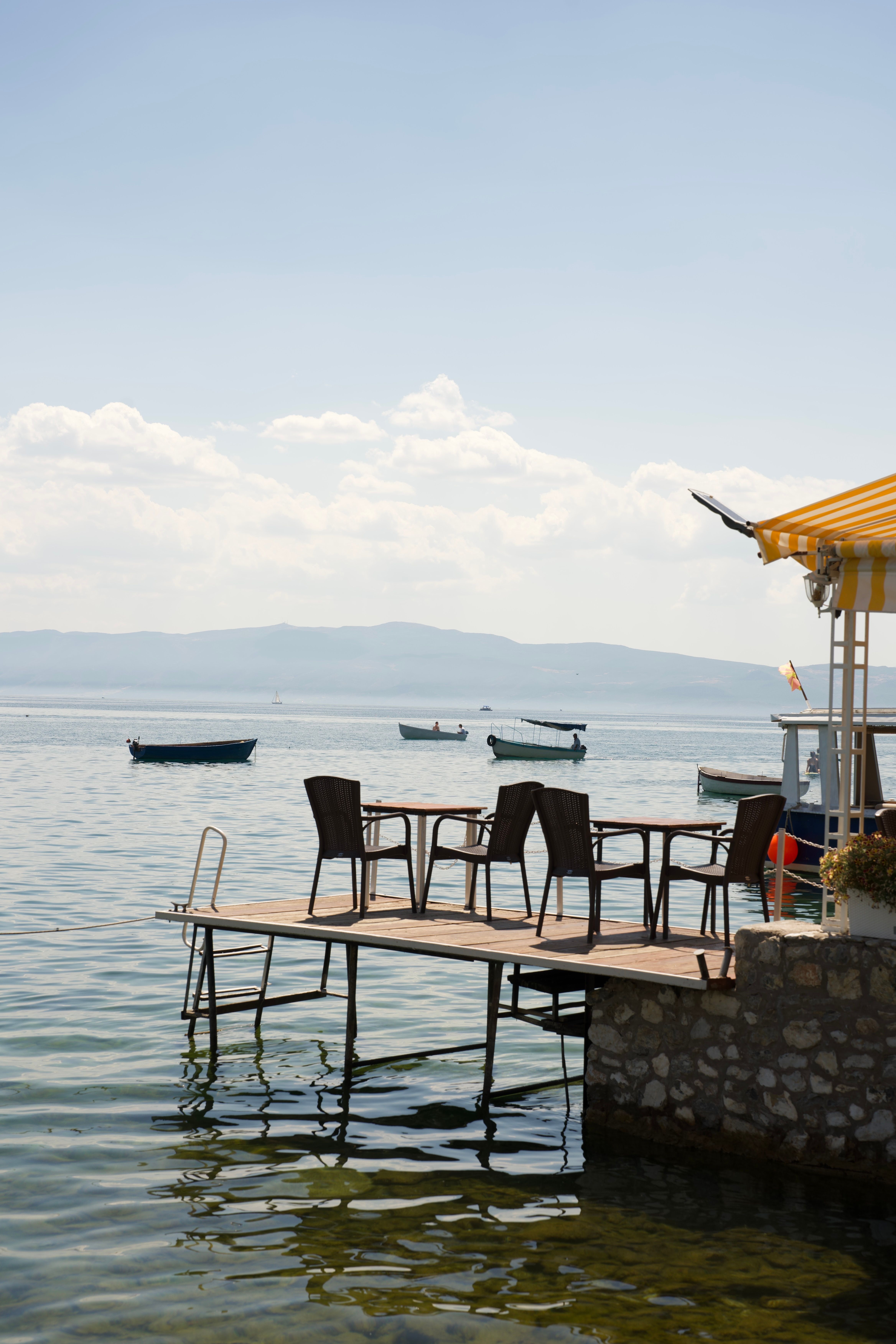 Charming Lakeside Seating with Boats on Water · Free Stock Photo