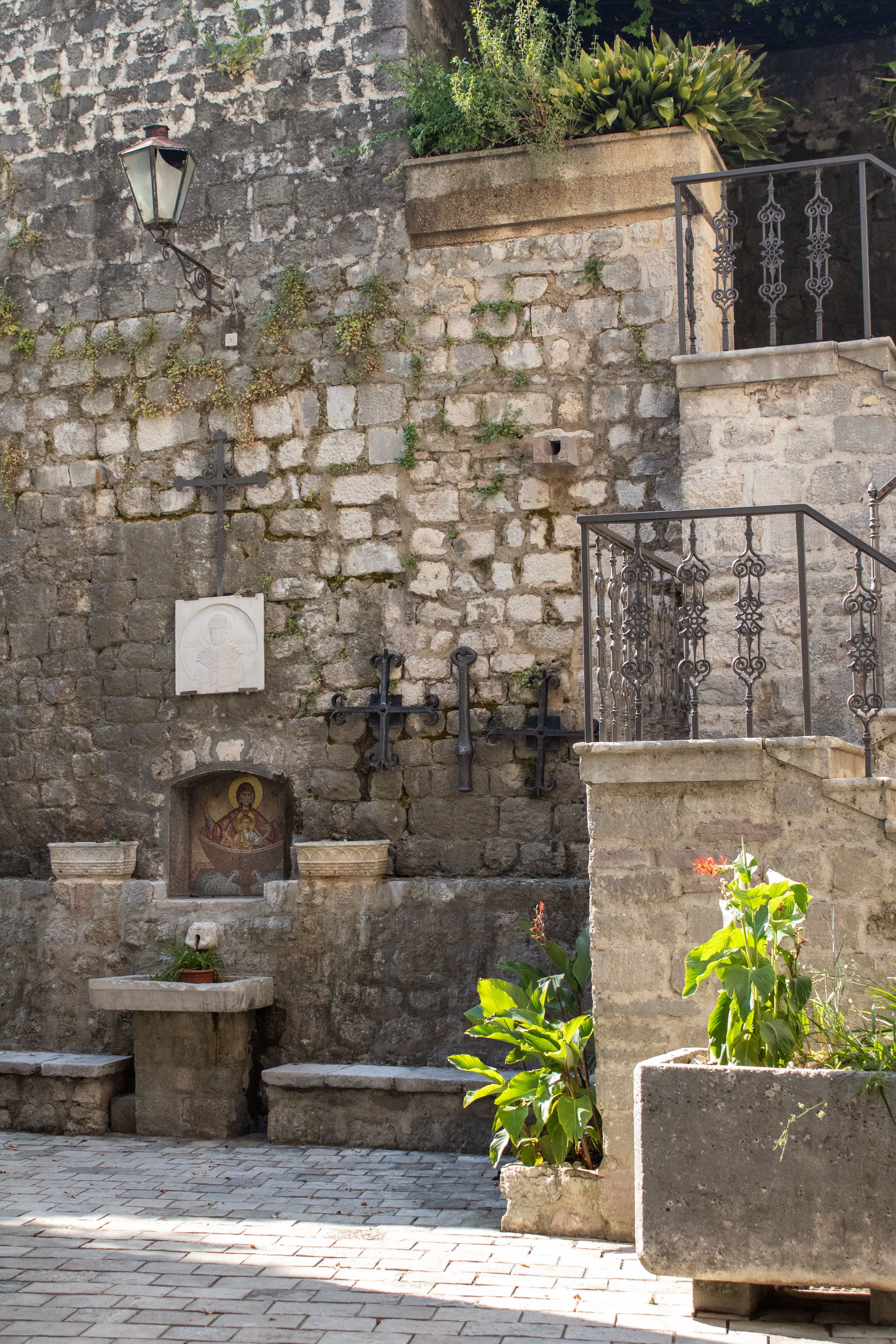 Historic Stone Wall with Religious Art and Plants · Free Stock Photo