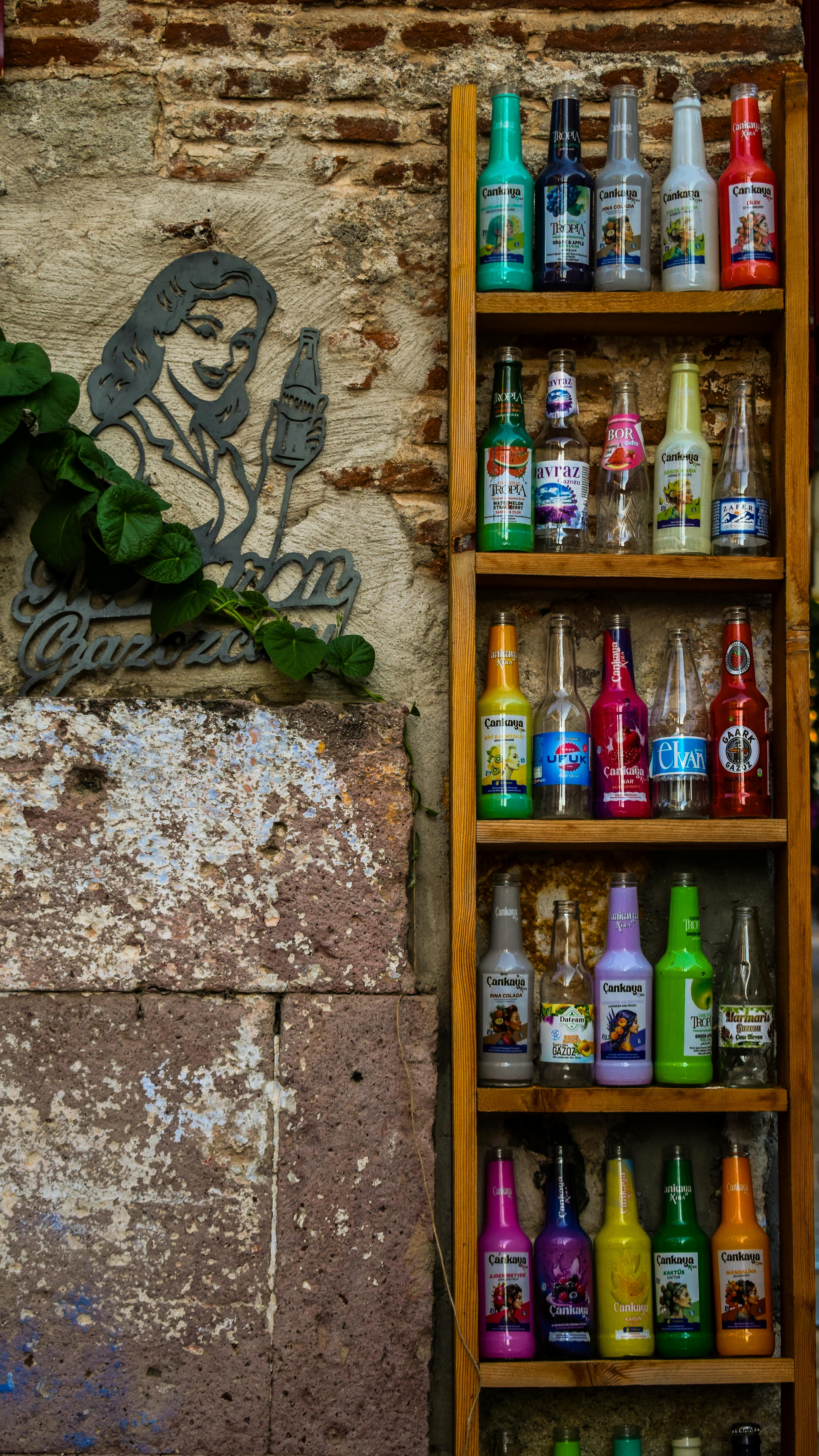 Colorful Beverage Bottles on Rustic Wall Display · Free Stock Photo