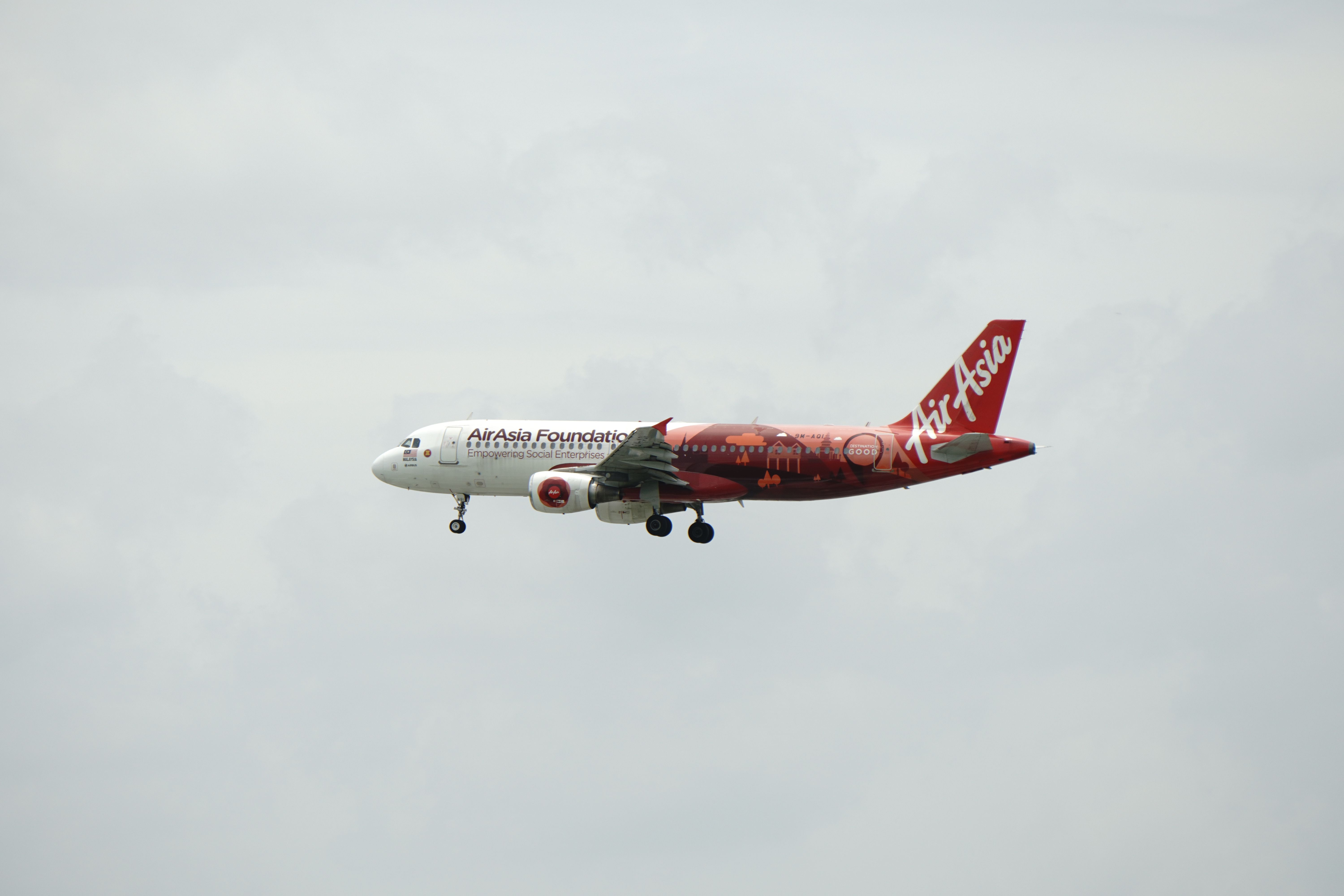 AirAsia Aircraft in Flight Against Cloudy Sky · Free Stock Photo