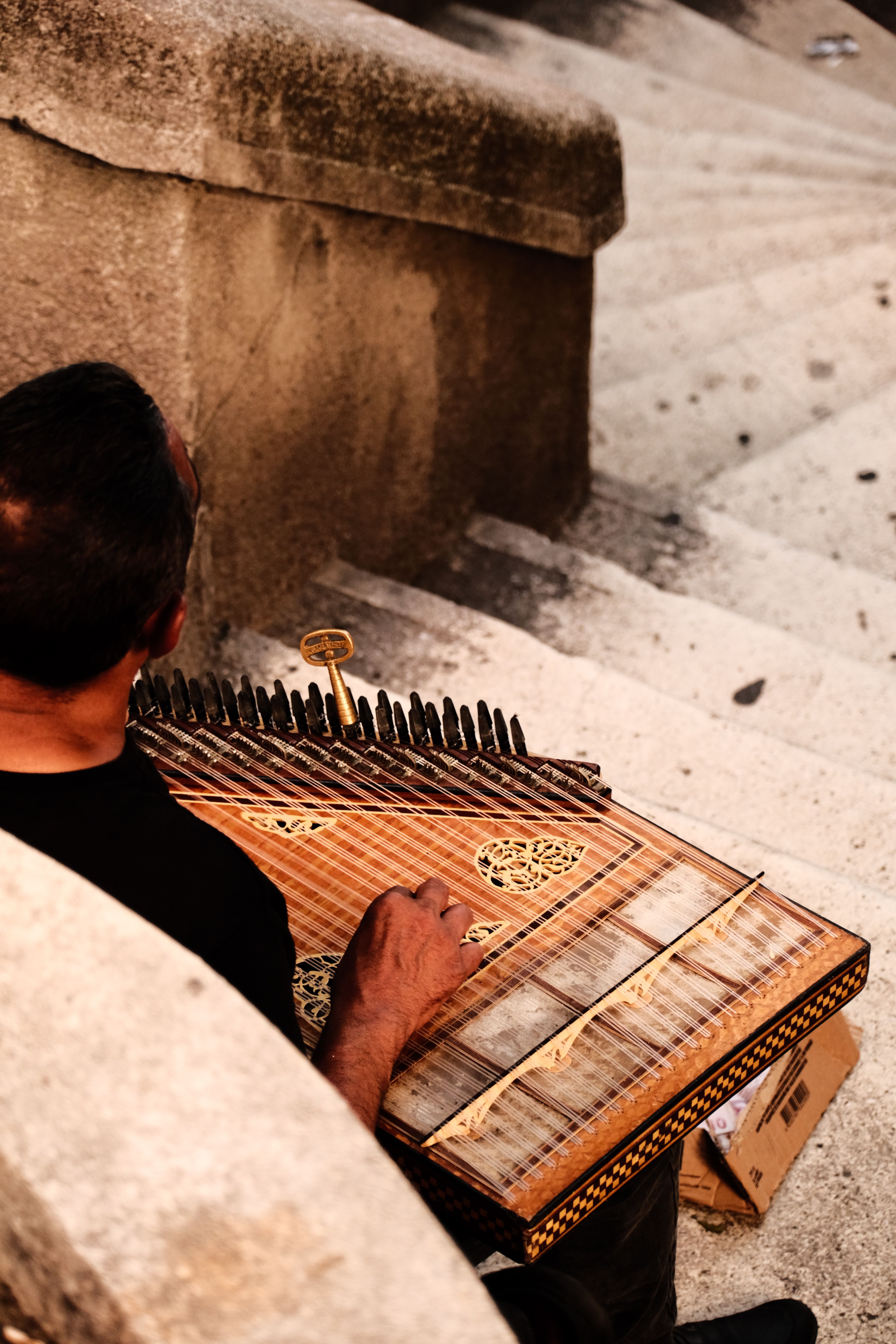 Musician Playing Traditional Instrument on Stone Steps · Free Stock Photo