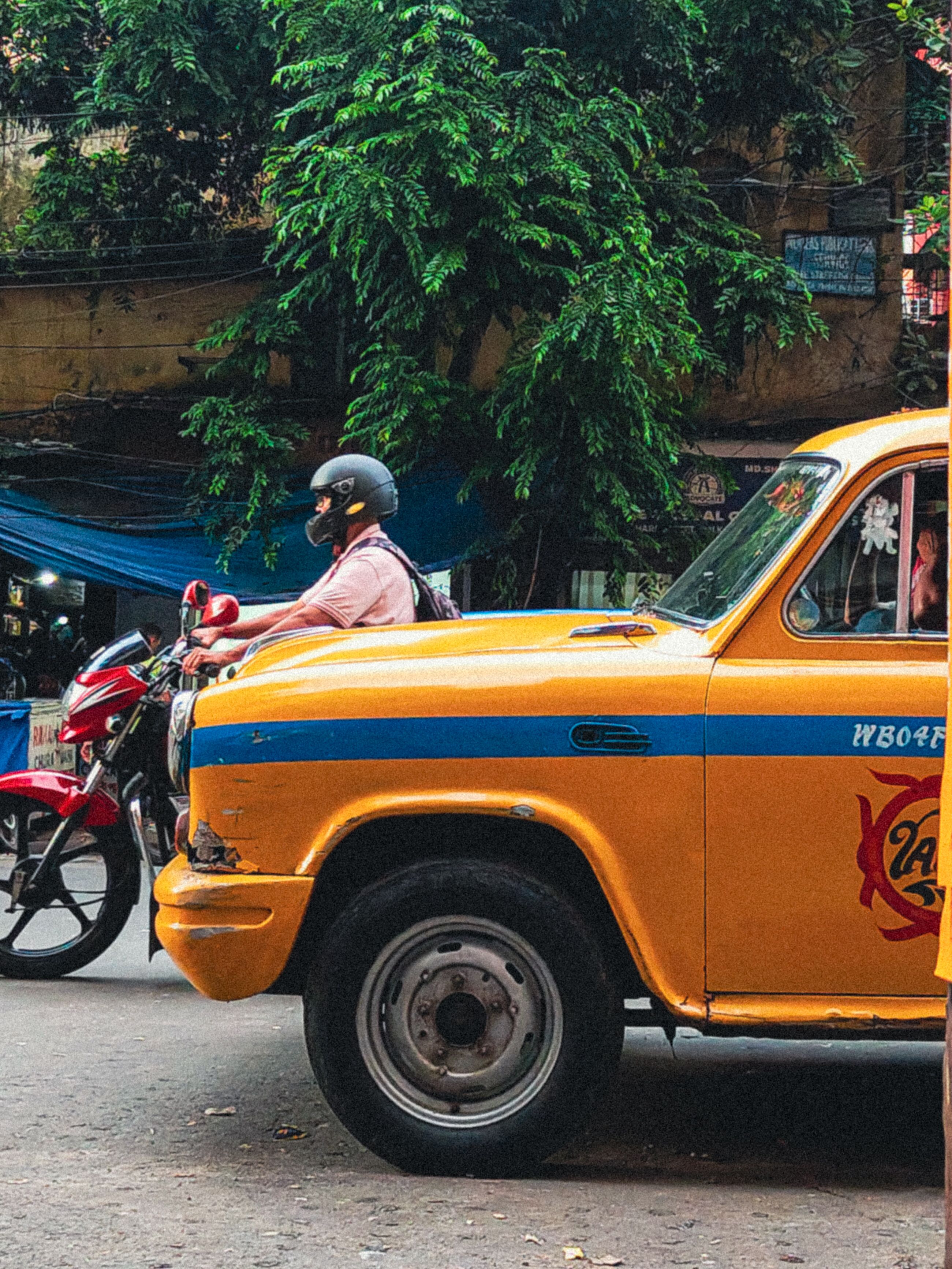 Yellow Taxi and Motorcyclist on Busy Street · Free Stock Photo
