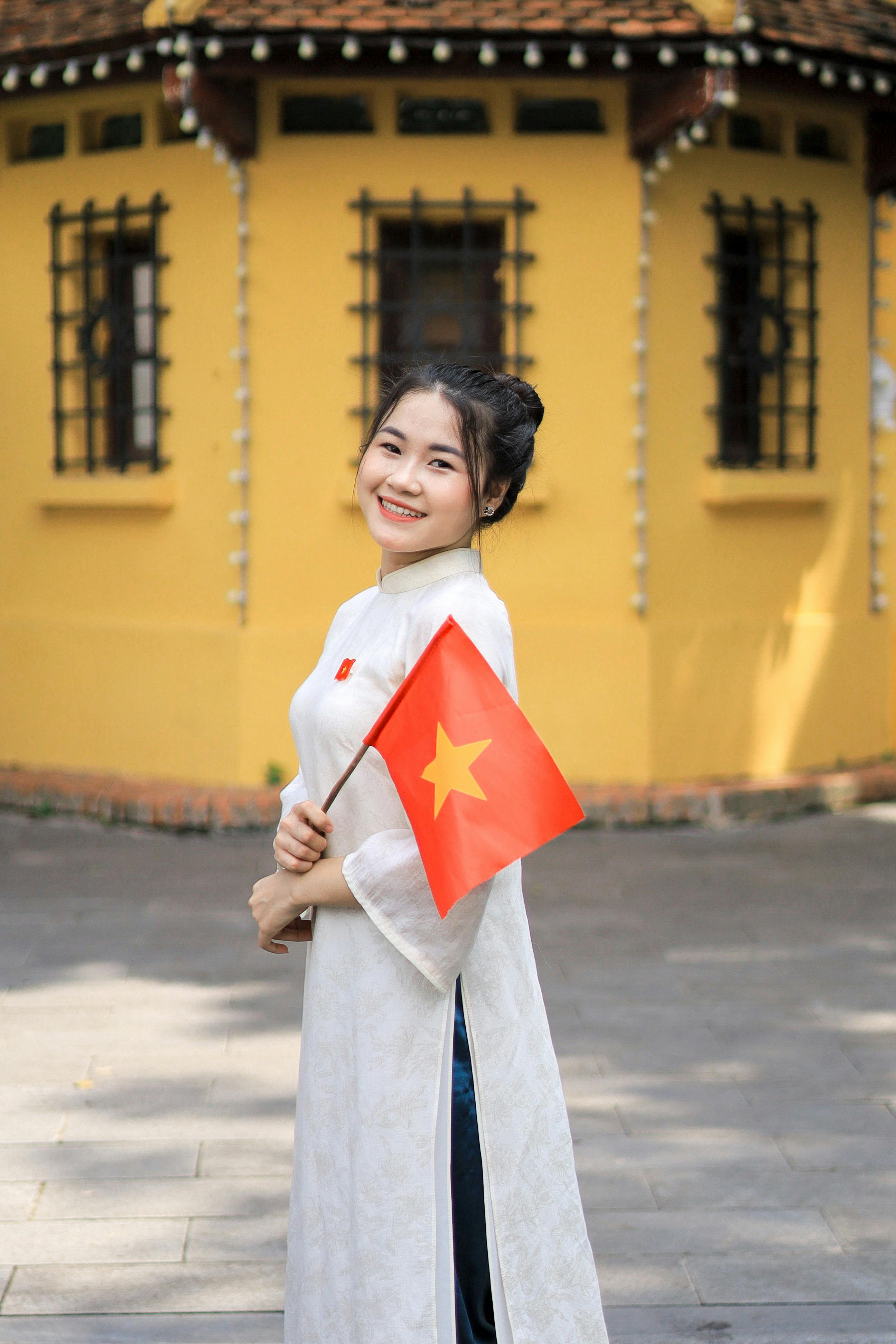 Young Woman in Traditional Vietnamese Ao Dai with Flag · Free Stock Photo
