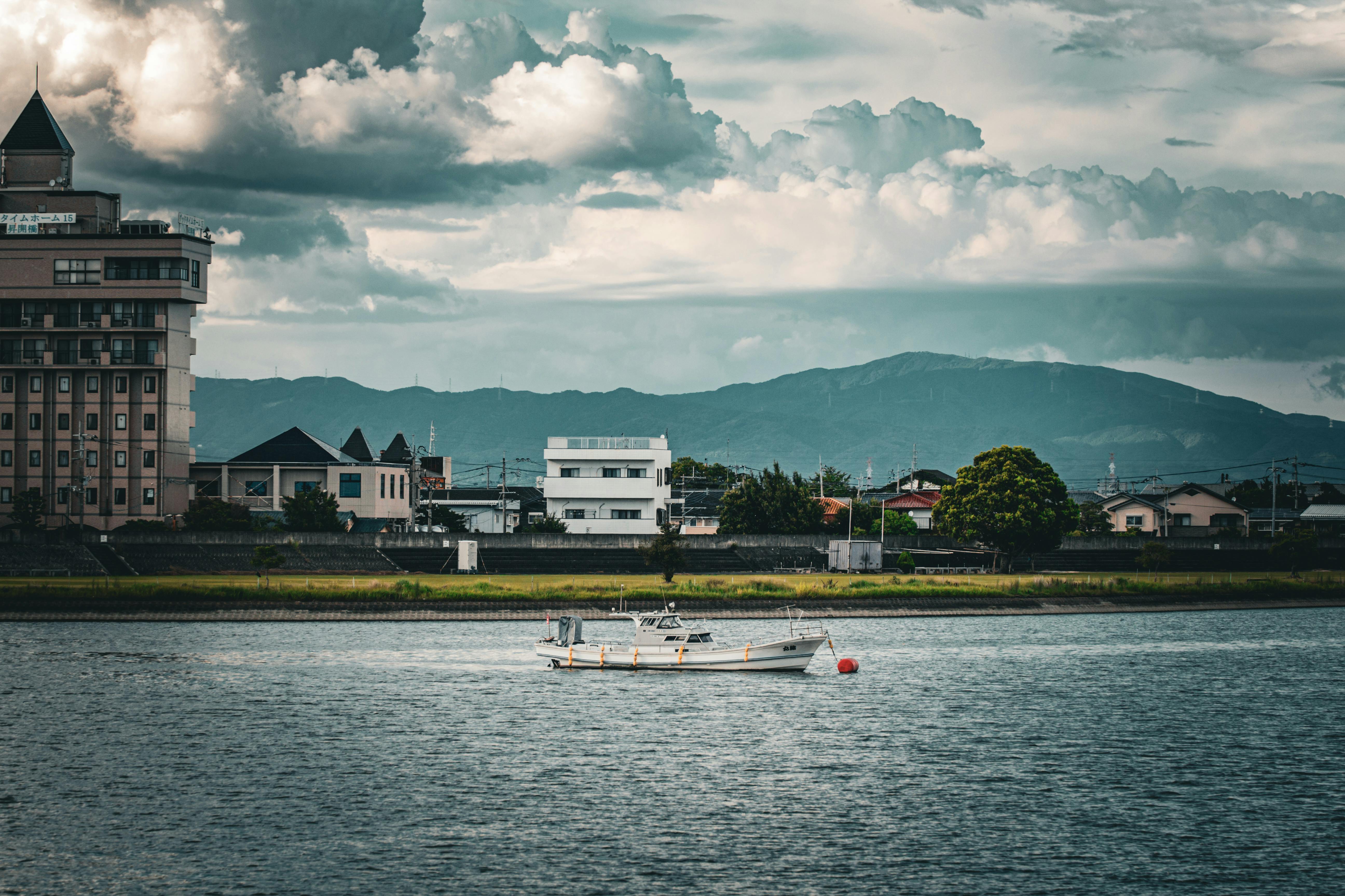 Scenic Riverside Town with Boat and Mountain View · Free Stock Photo