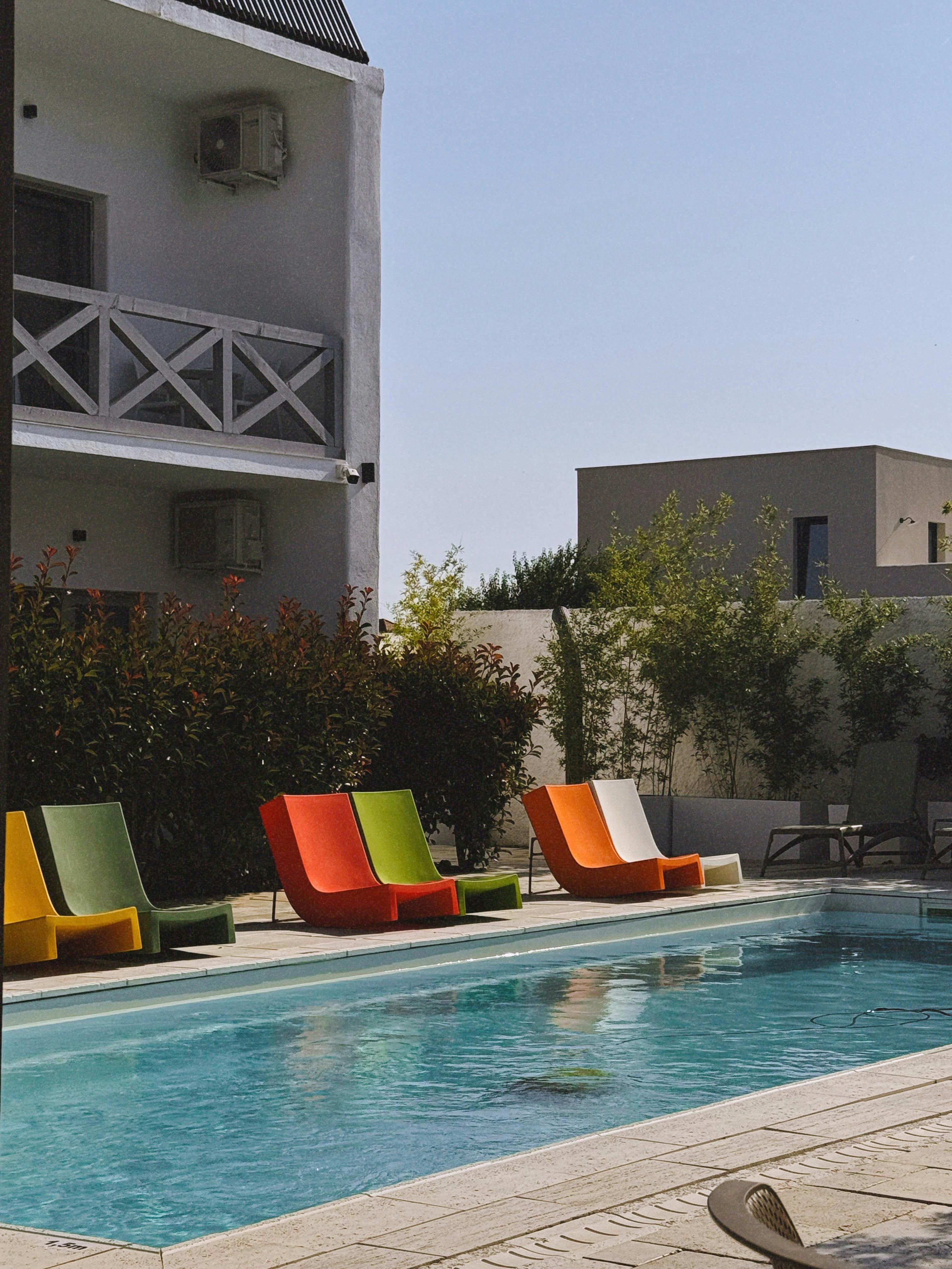 Vibrant Poolside with Colorful Lounge Chairs · Free Stock Photo