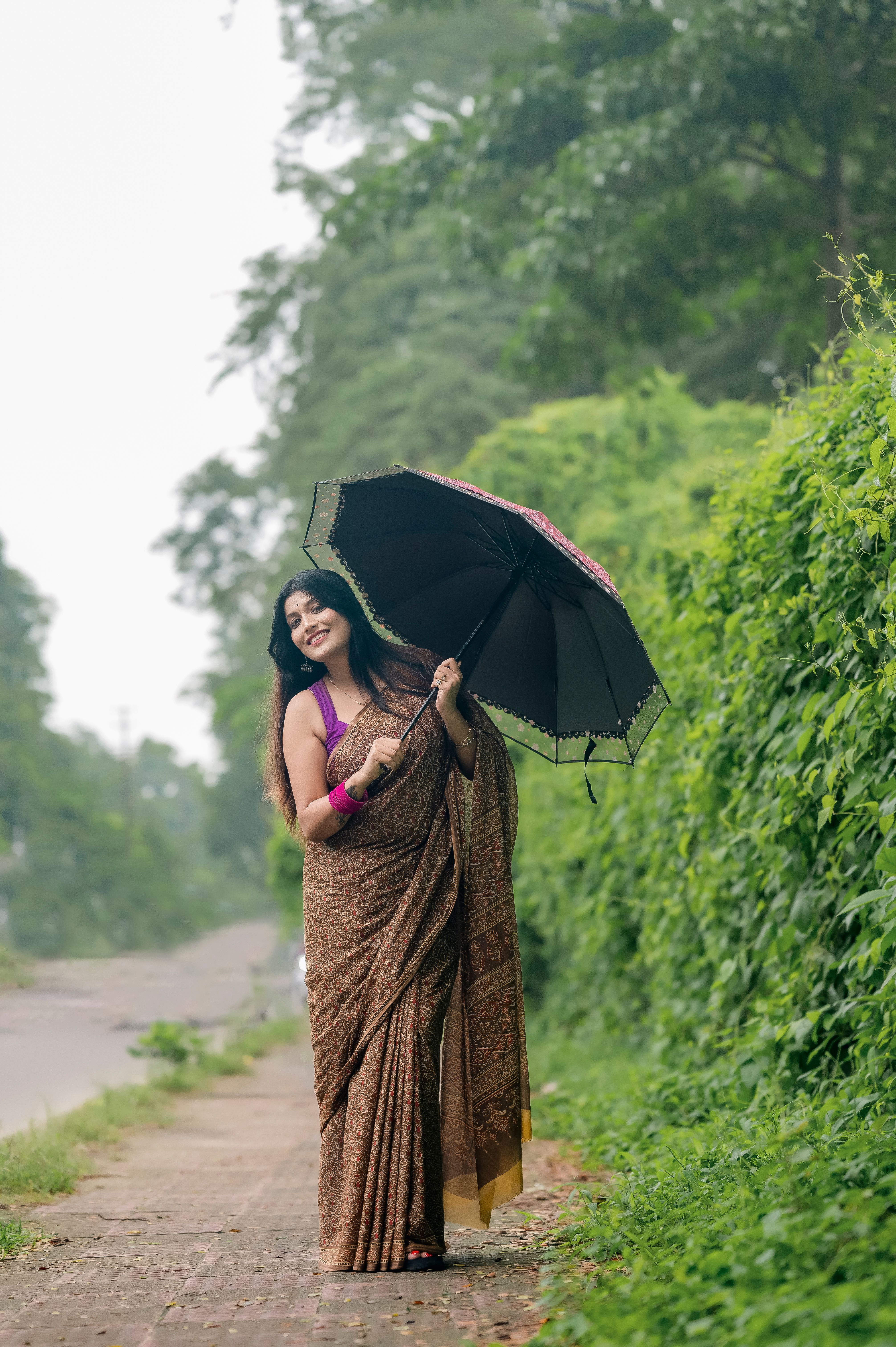 Woman in Saree Walking with Umbrella on Green Pathway · Free Stock Photo
