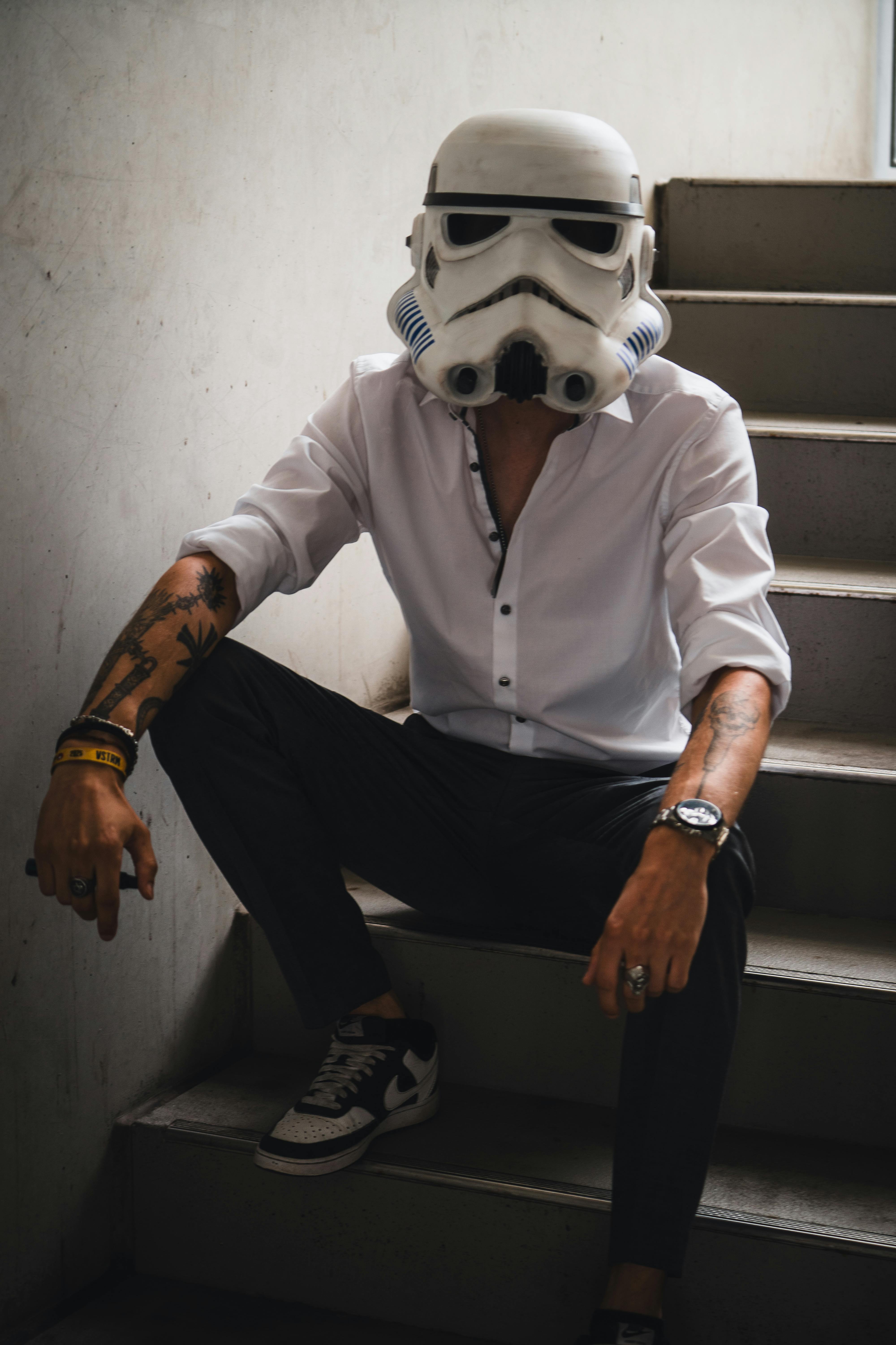 Modern Stormtrooper Sits on Staircase in White Shirt · Free Stock Photo