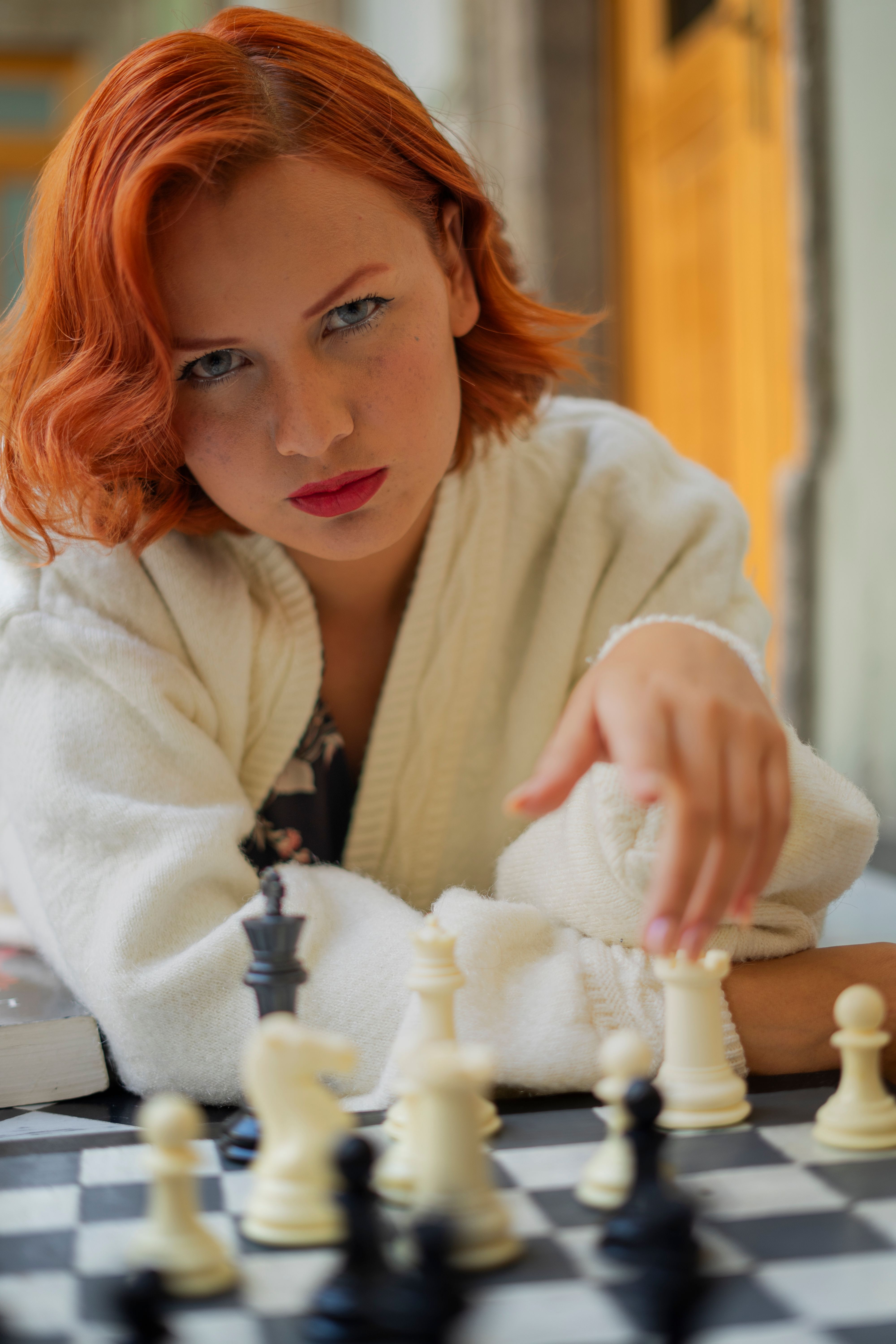Woman Strategizing Chess Move in Cozy Attire · Free Stock Photo