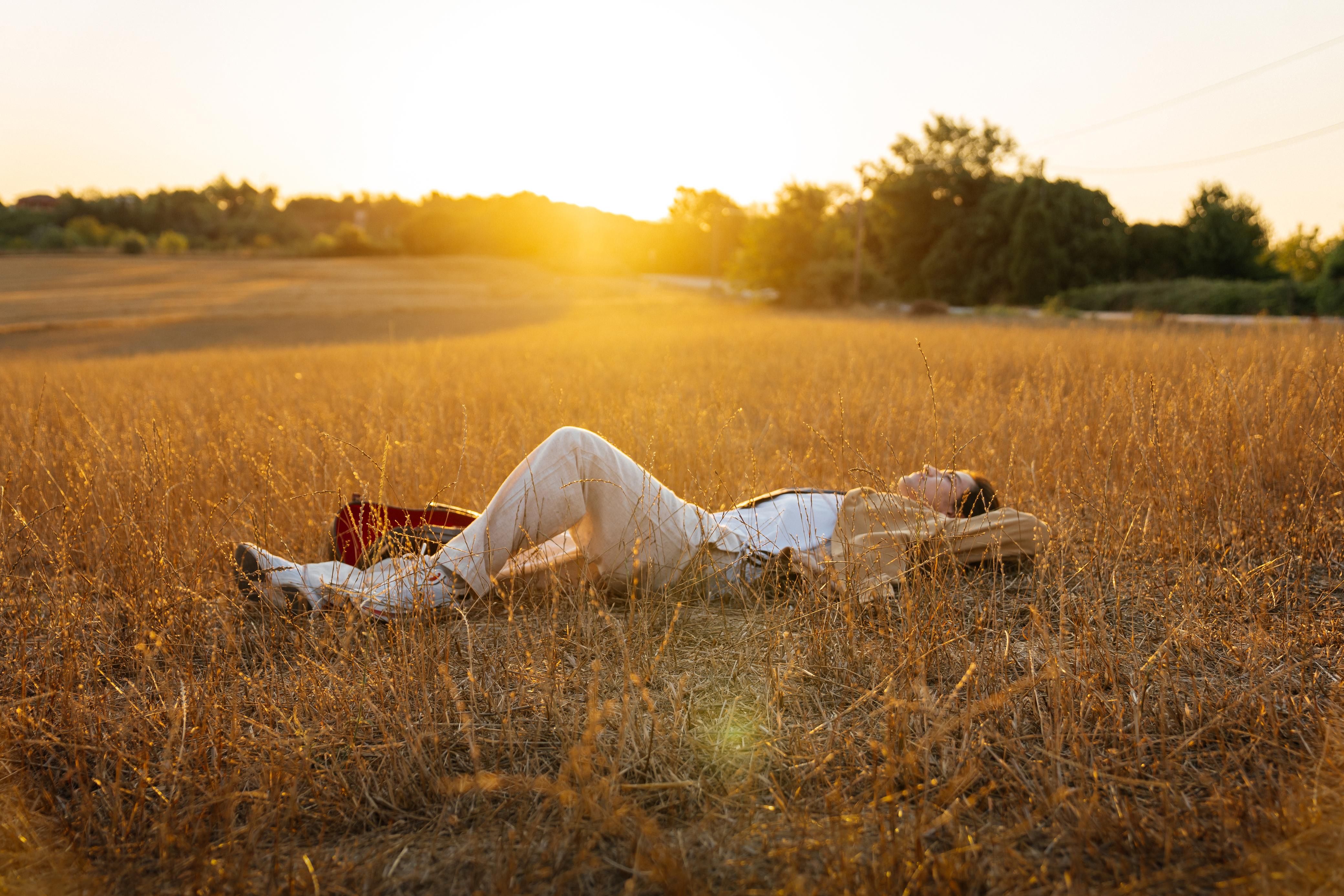 Relaxed Woman Lying in Sunny Field at Sunset · Free Stock Photo
