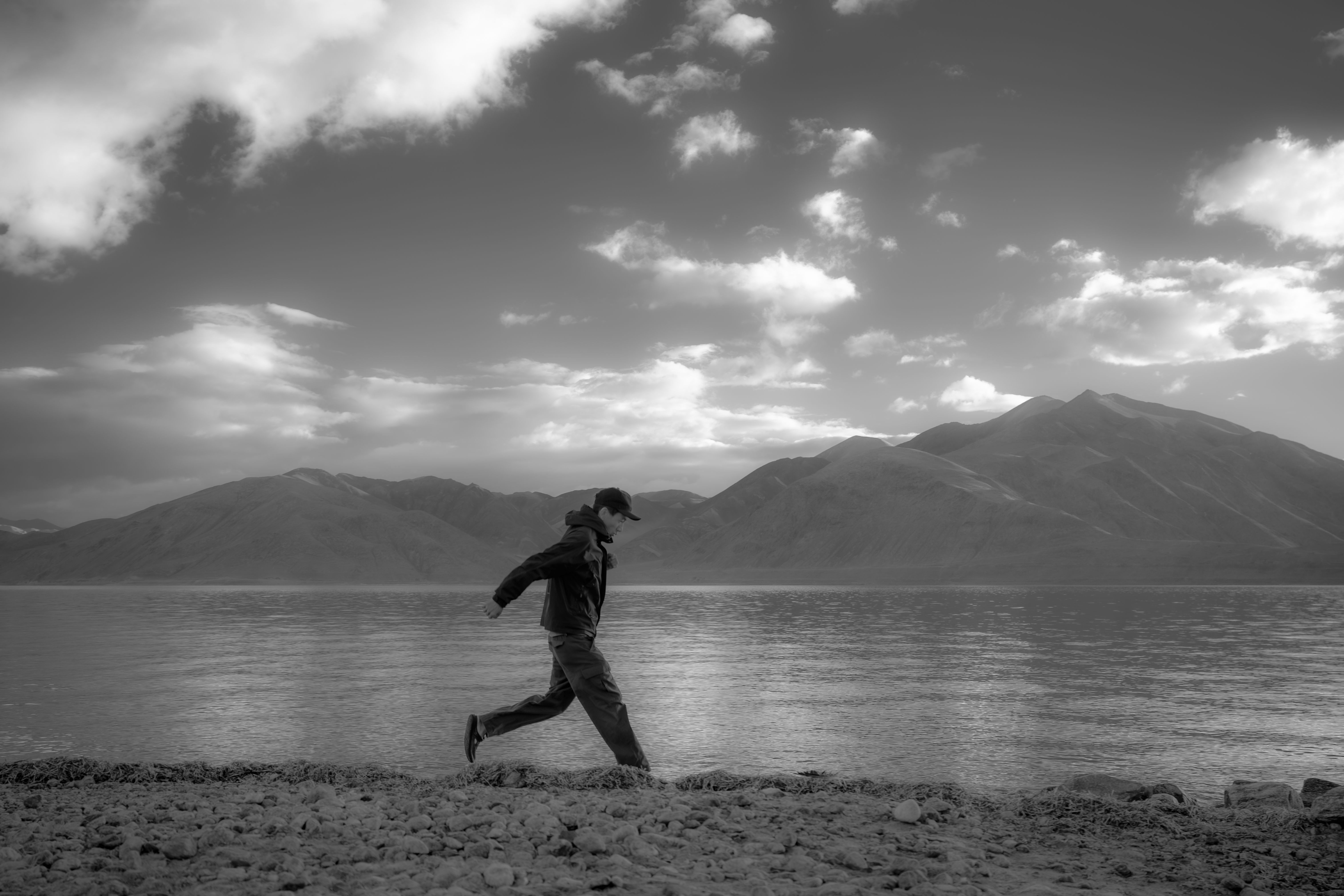 Man Jogging Along Mountain Lake with Dramatic Sky · Free Stock Photo