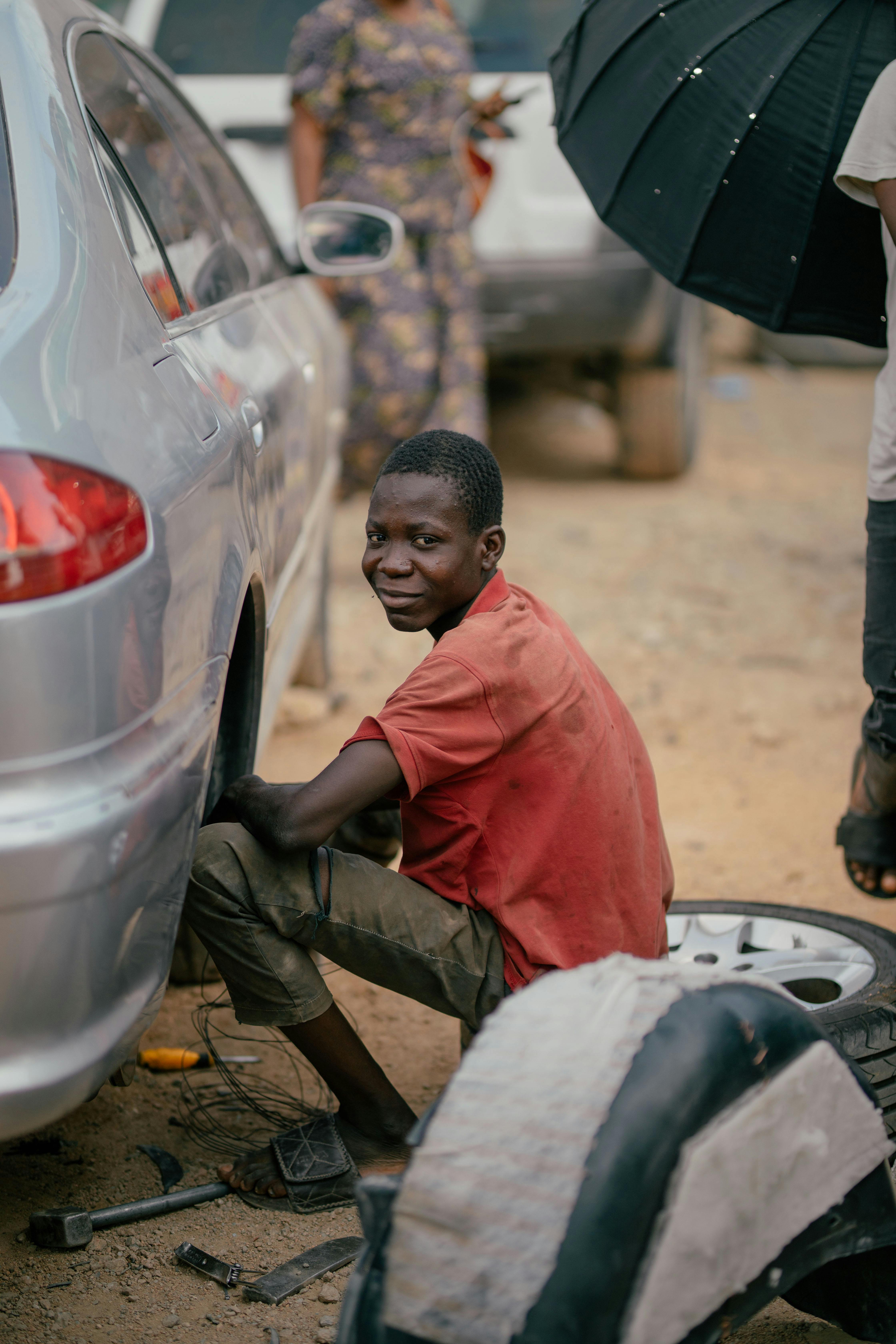 Young Mechanic Working on a Car Tire Outdoors · Free Stock Photo