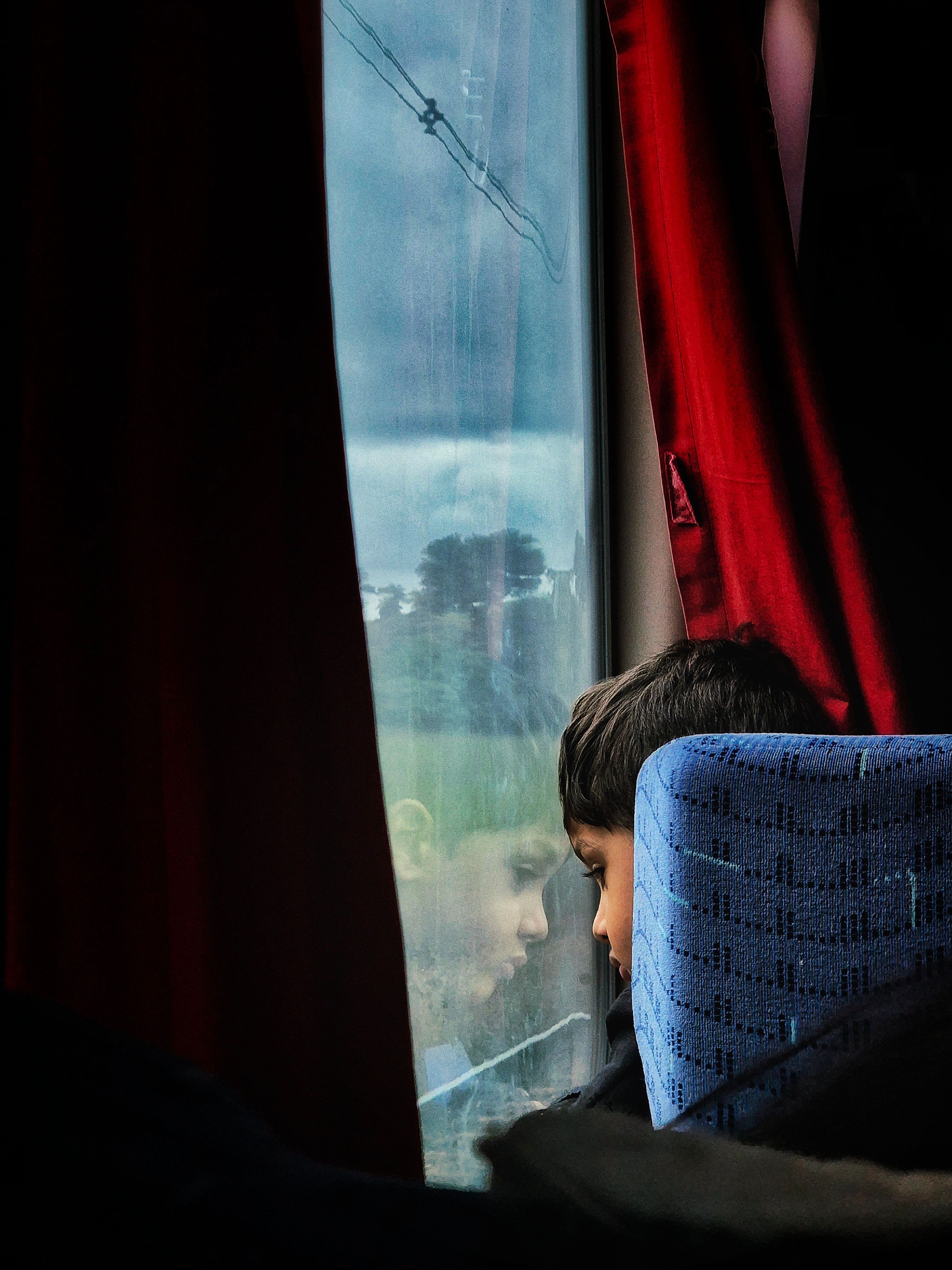 Reflective Child Gazing Out Train Window · Free Stock Photo