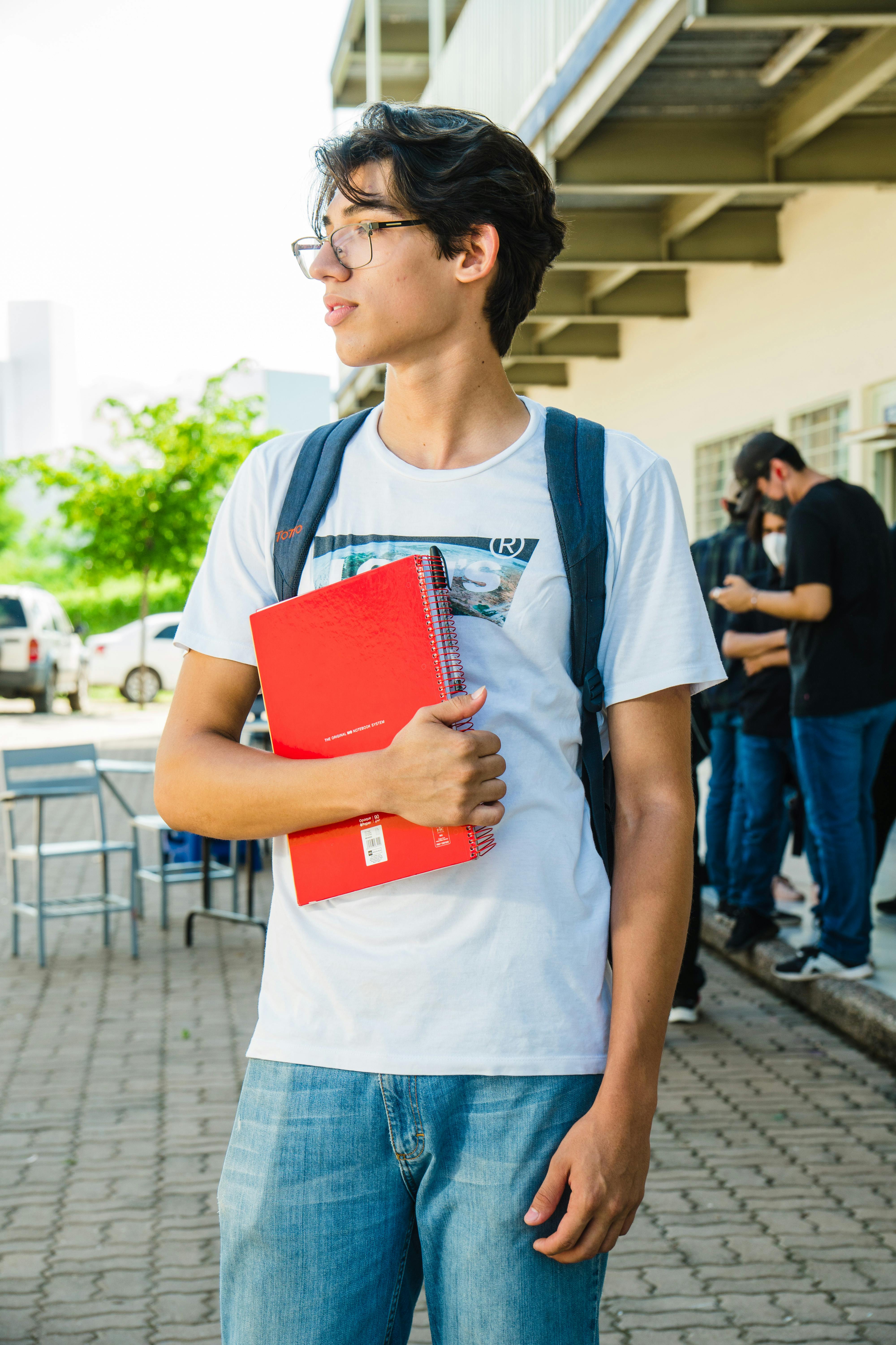 University Student Holding a Notebook Outdoors · Free Stock Photo