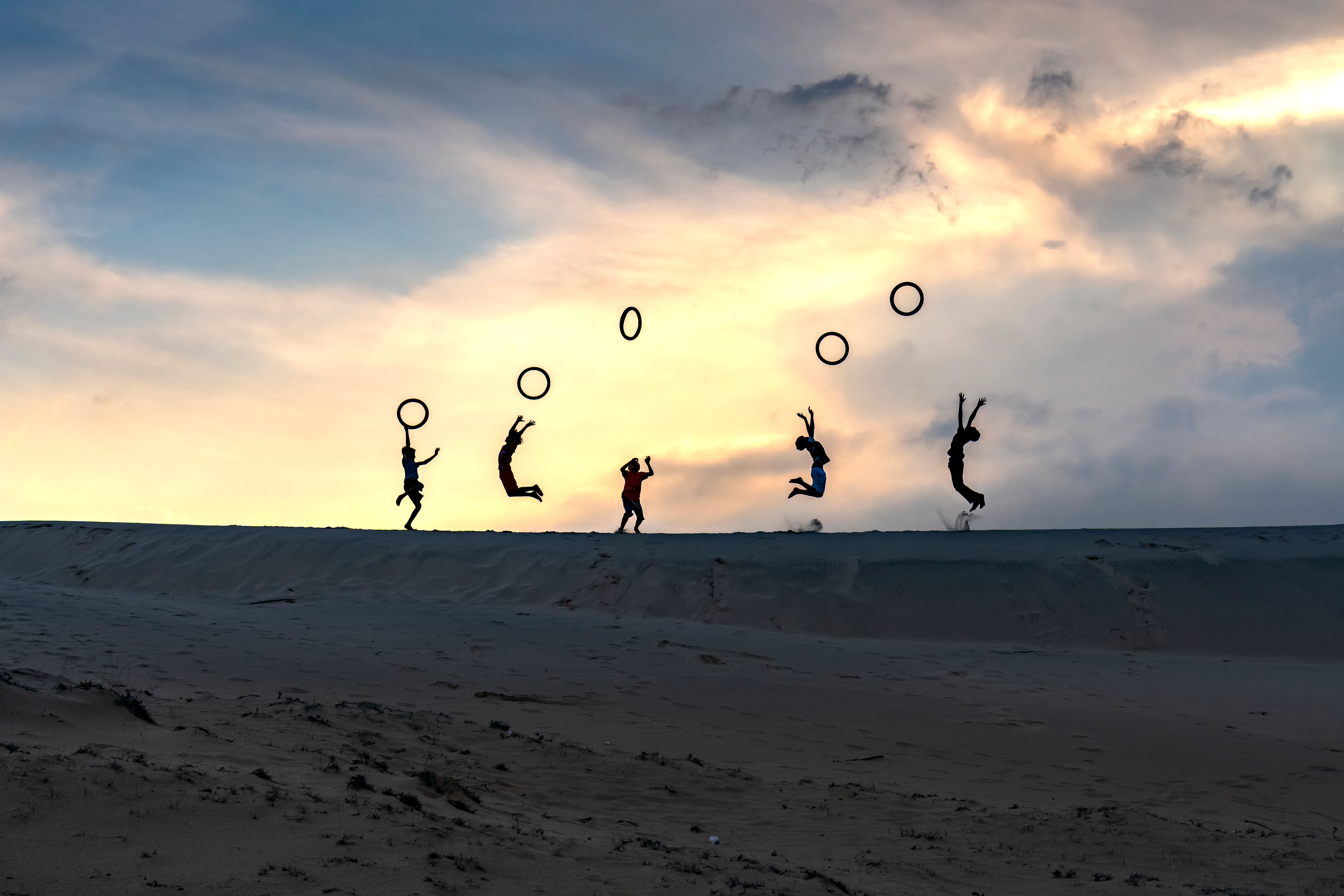 Silhouette of People Jumping with Hoops at Sunset · Free Stock Photo