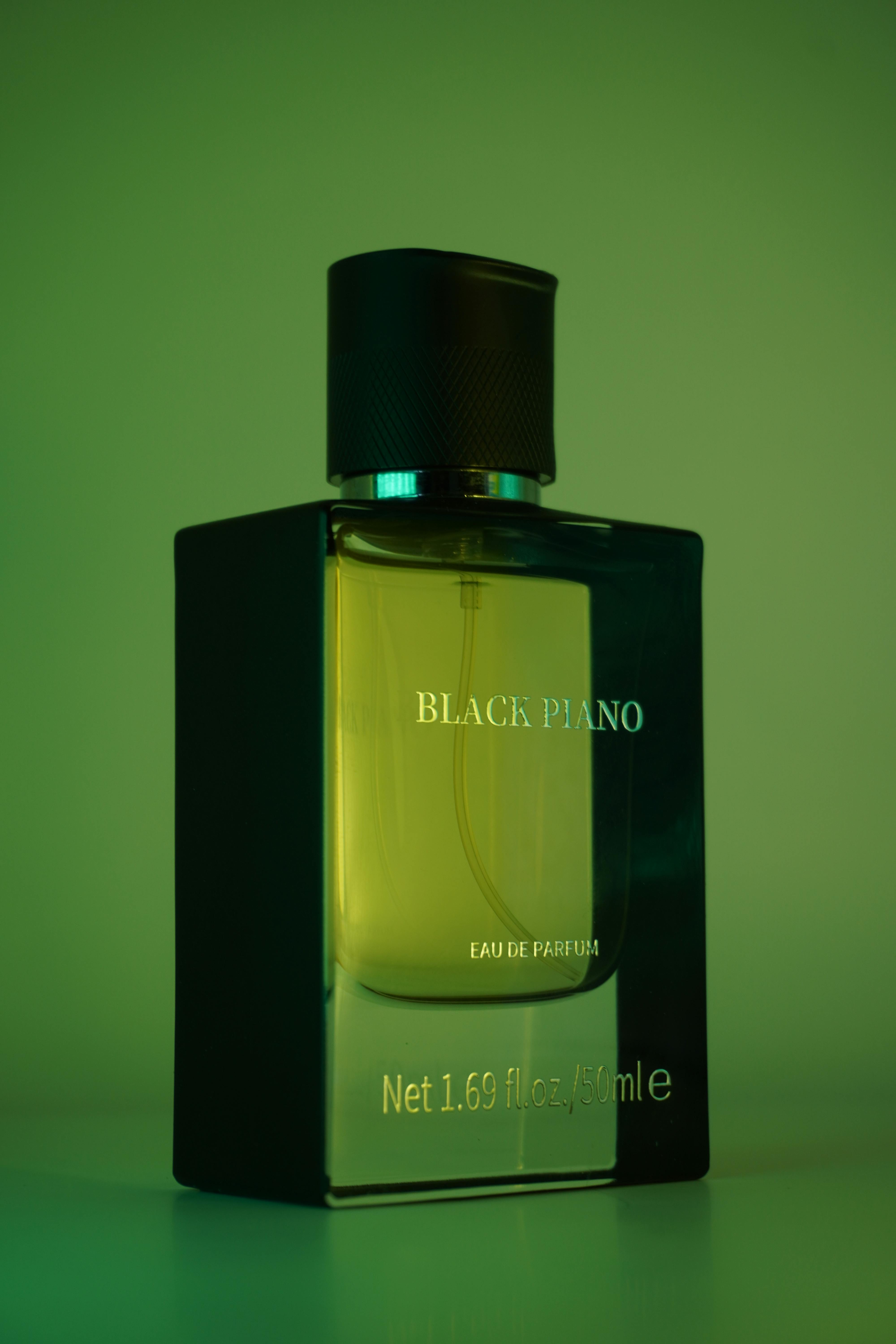 Elegant Black Piano Perfume Bottle with Green Hue · Free Stock Photo