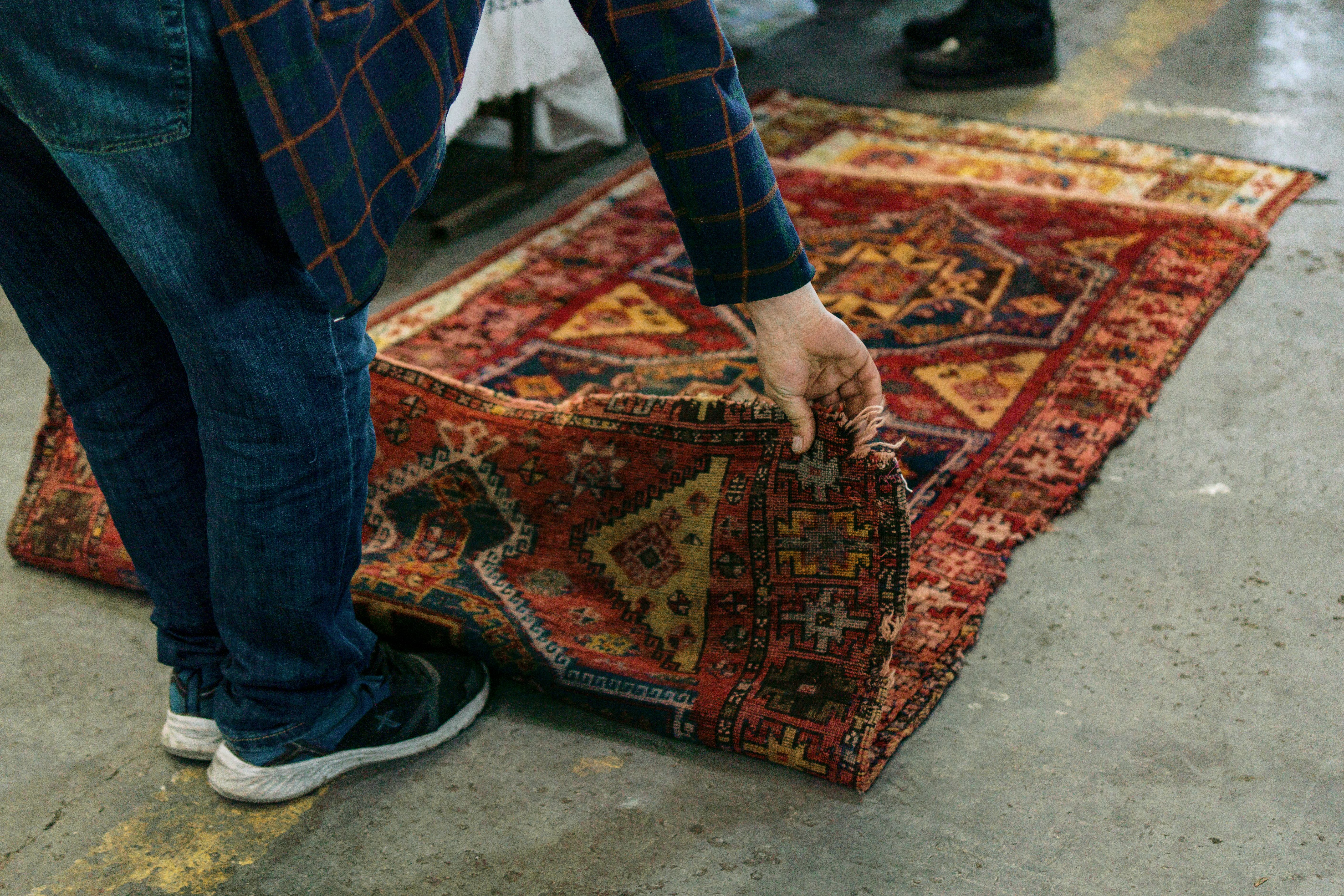 Man Handling Vintage Persian Rug Indoors · Free Stock Photo