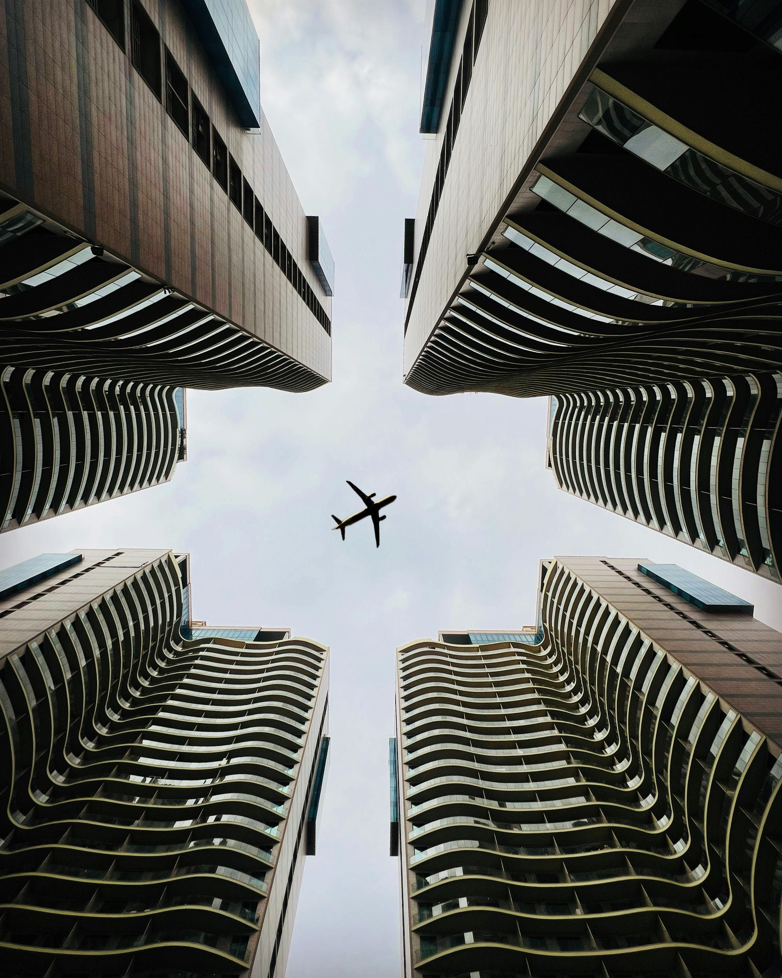 Modern Architectural Cityscape with Airplane Above · Free Stock Photo
