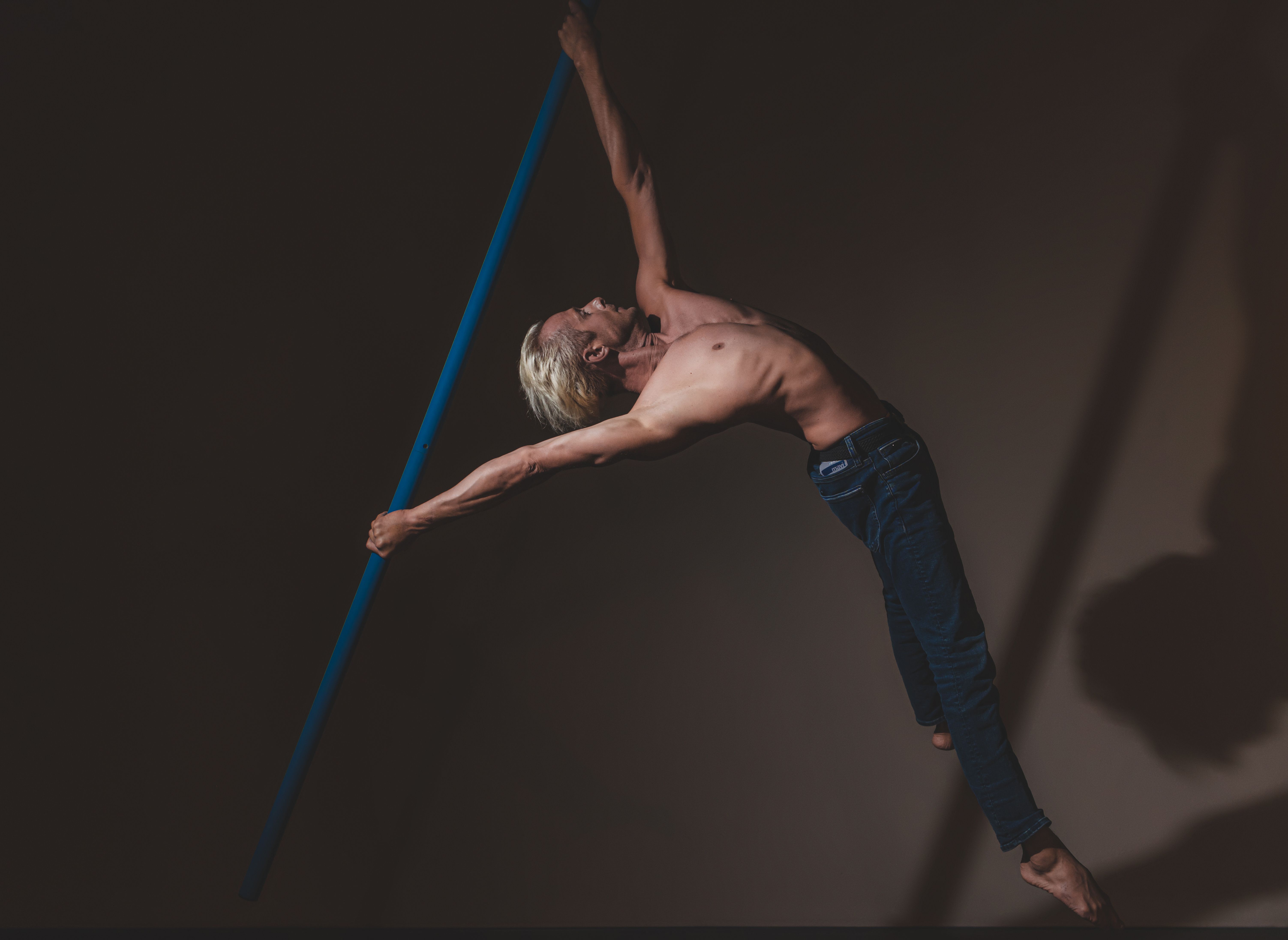 Dynamic Pole Dance Pose in Dim Studio Light · Free Stock Photo