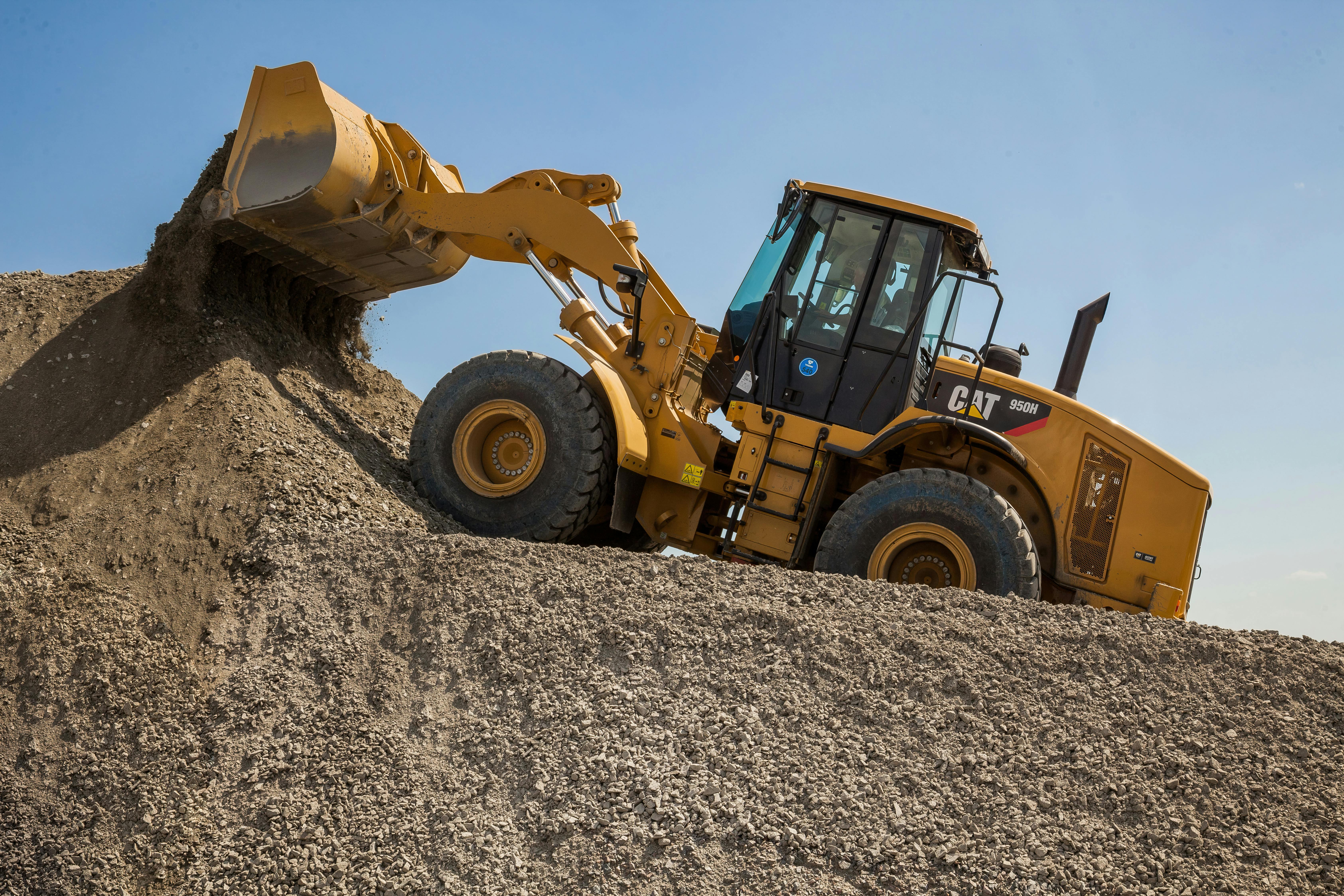 Orange and Black Tractor Next to Piles of Rocks · Free Stock Photo