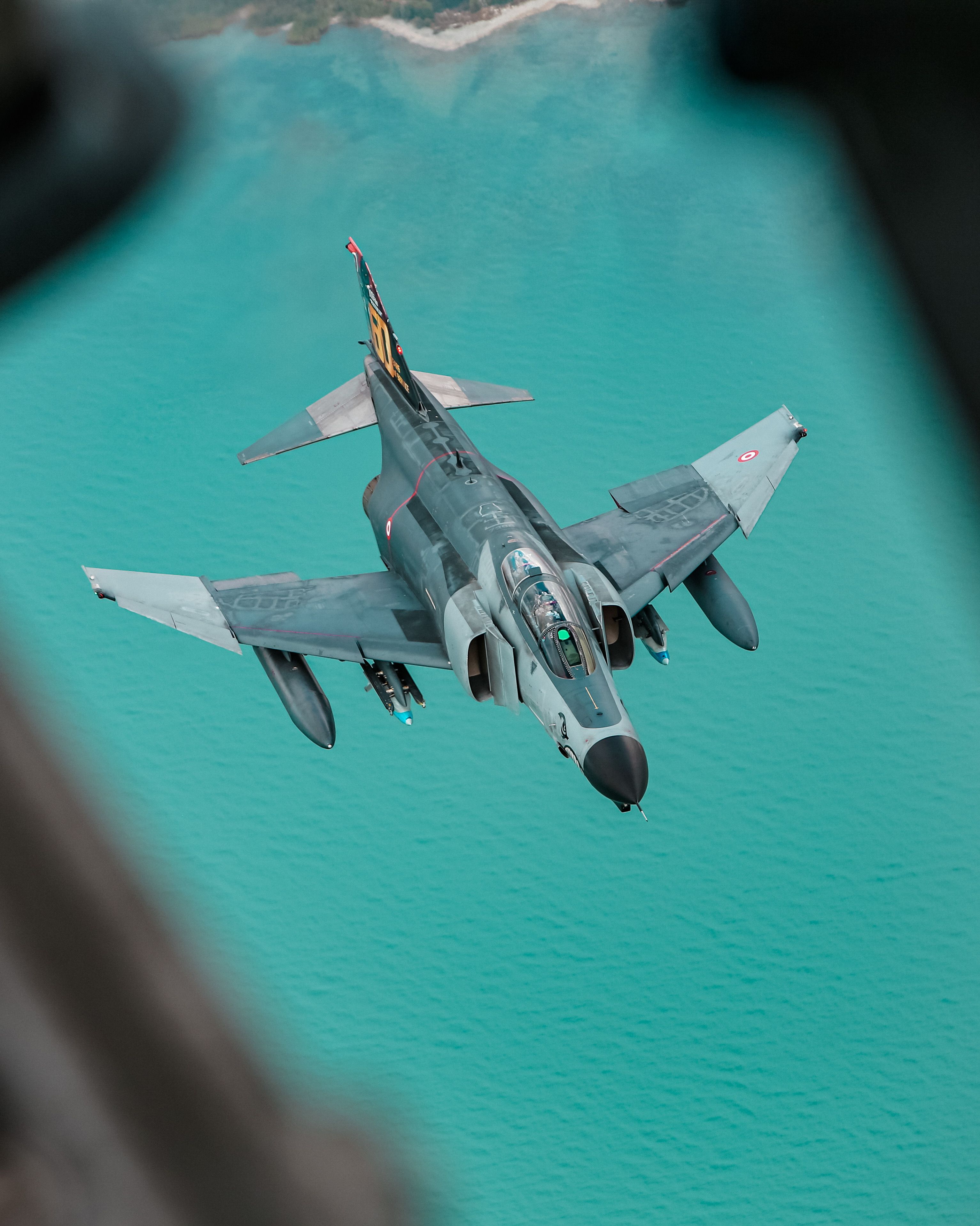 Fighter Jet Flying Over Turquoise Ocean Waters · Free Stock Photo