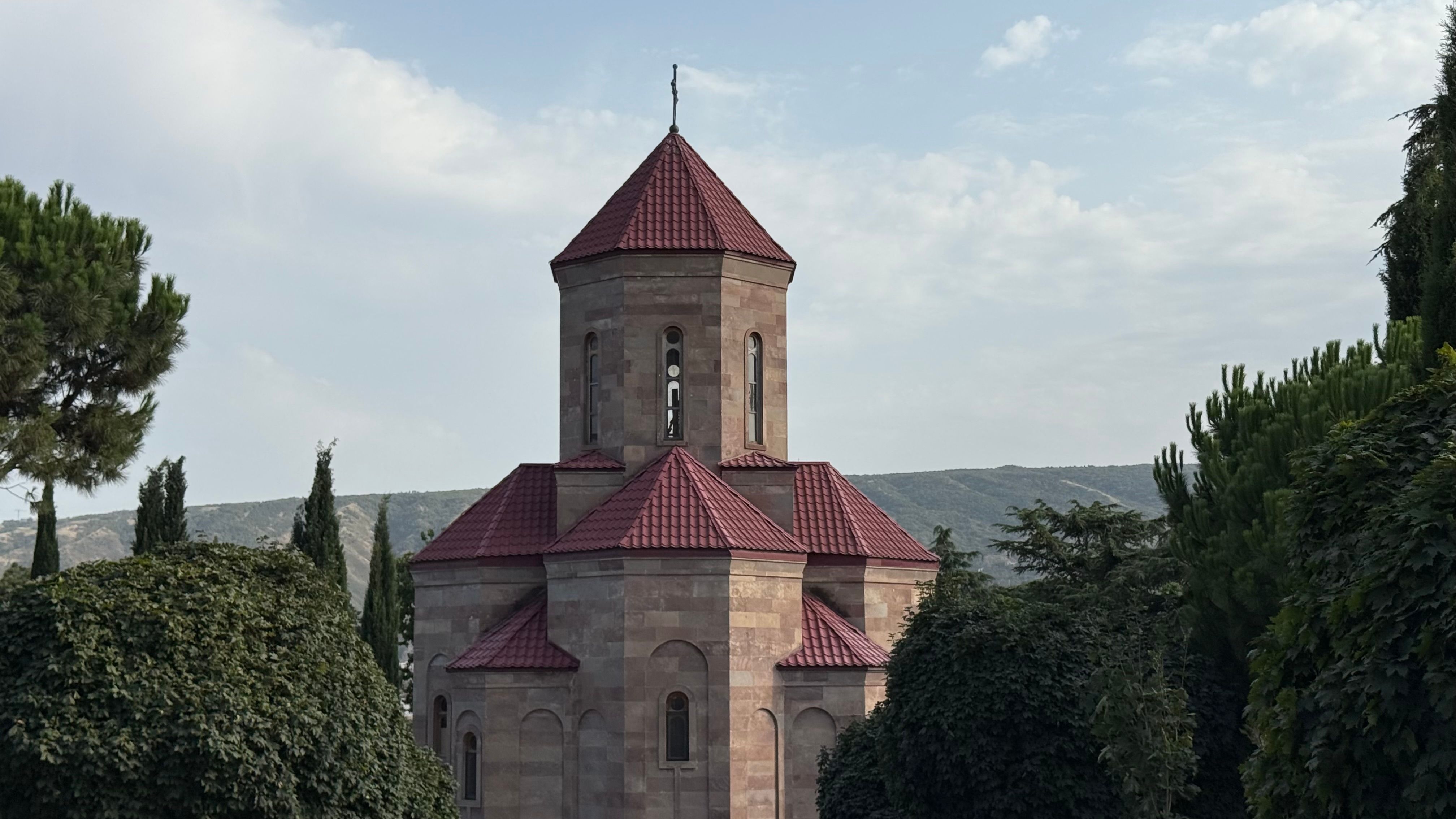 Red-roofed Stone Church Amid Verdant Foliage · Free Stock Photo