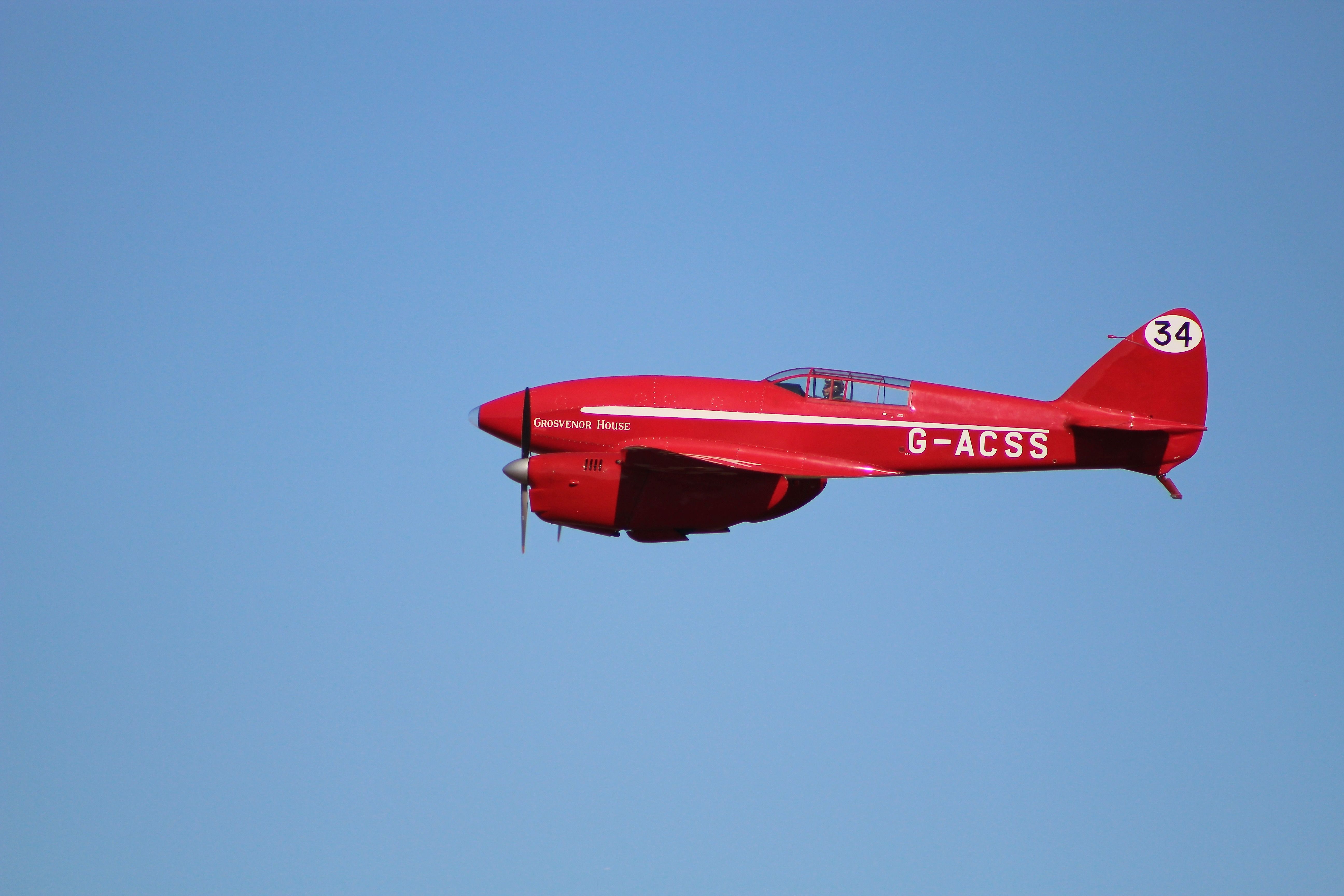 Vintage Red Aircraft Flying High in Blue Sky · Free Stock Photo
