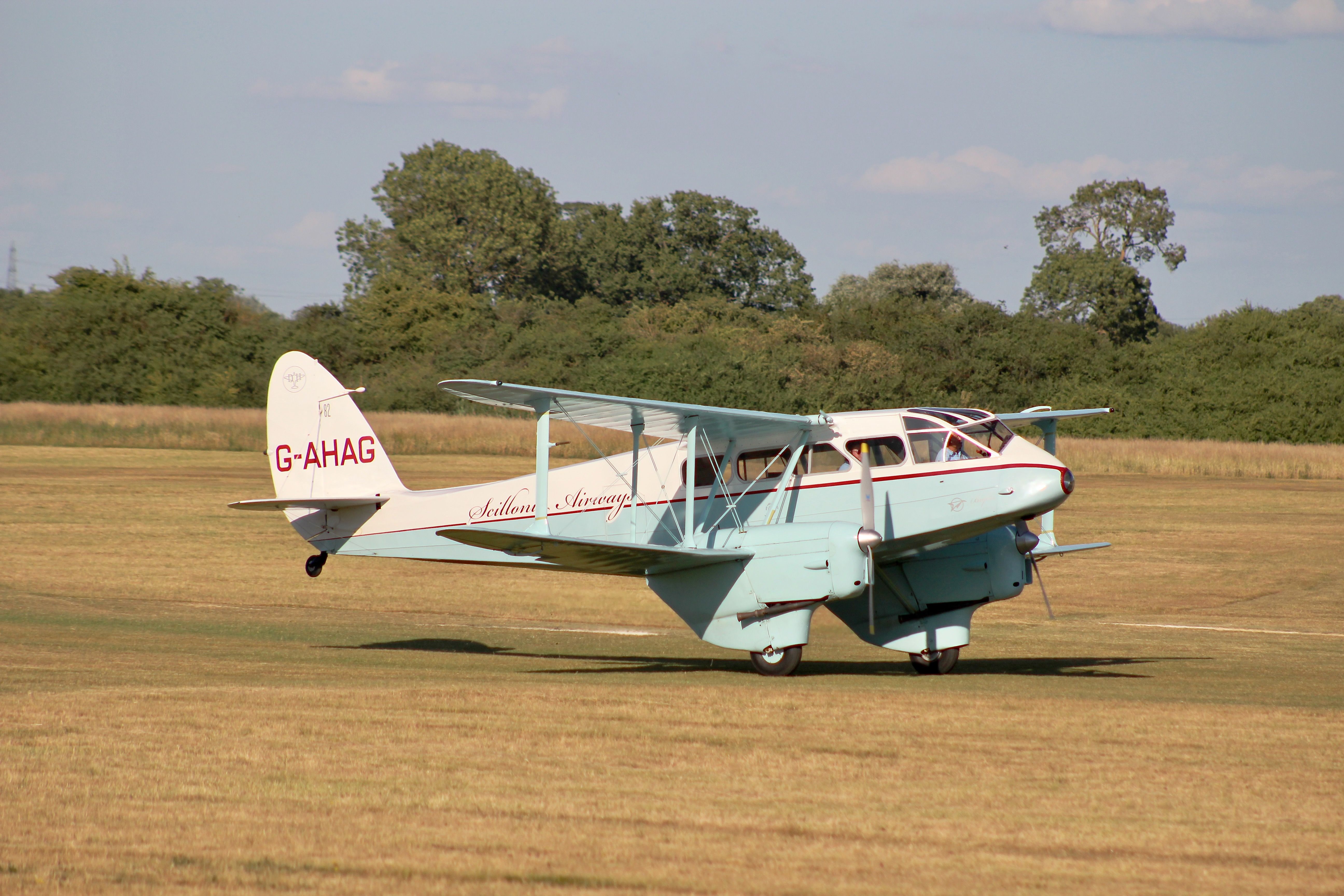 Classic Biplane Parked on Sunny Aerodrome · Free Stock Photo