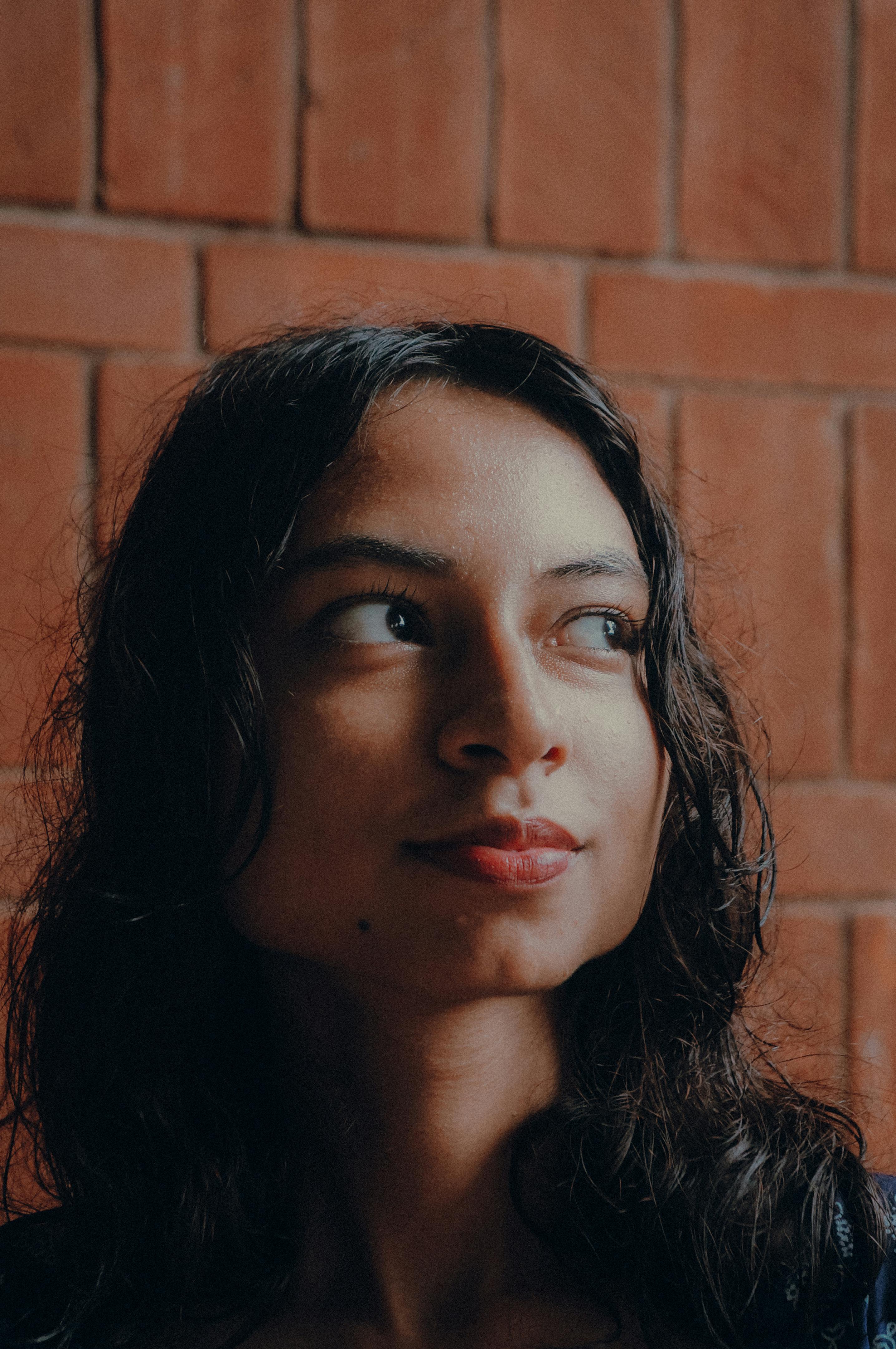 Pensive Woman Against Brick Wall Background · Free Stock Photo