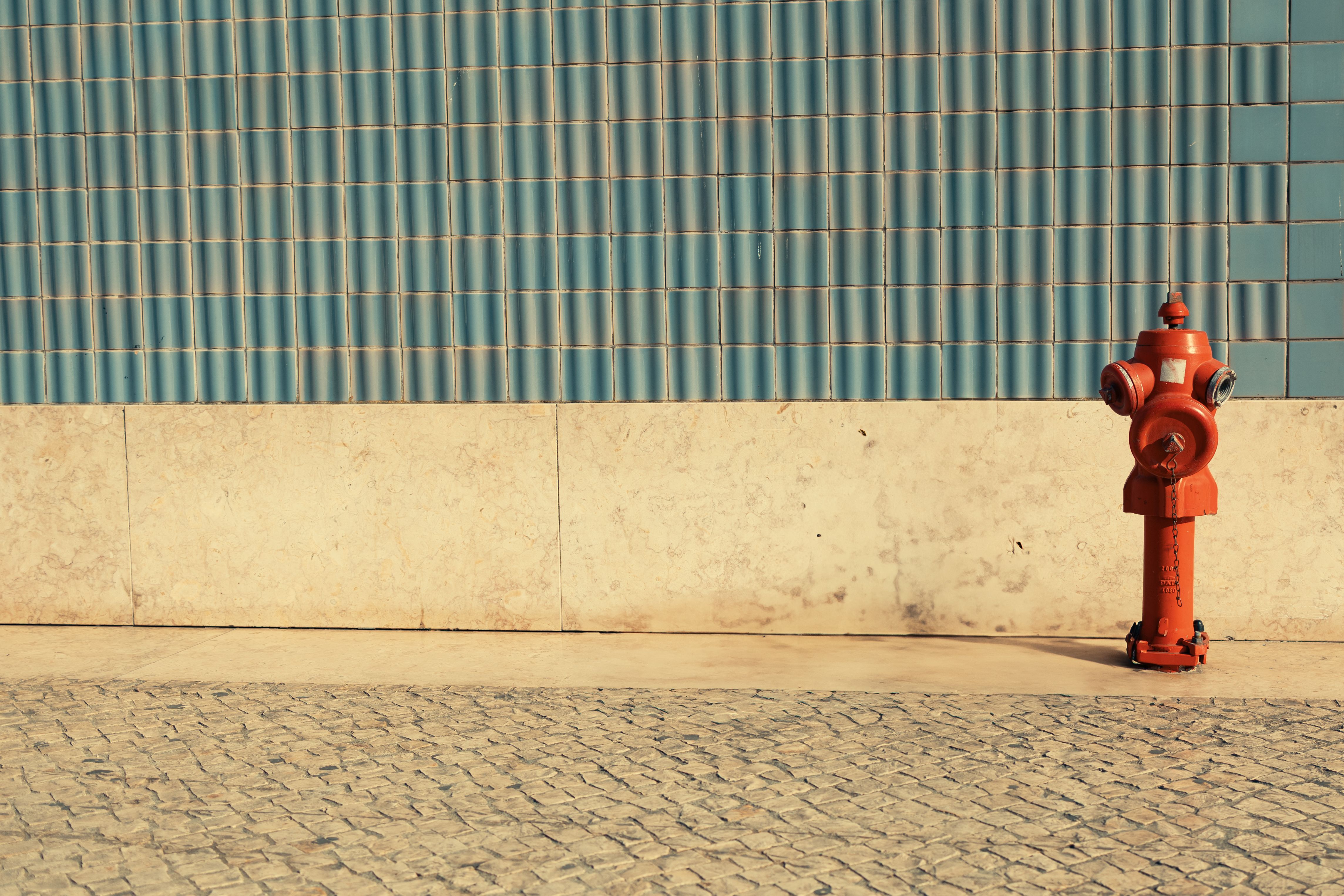 Orange Fire Hydrant Against Blue Tiled Wall · Free Stock Photo