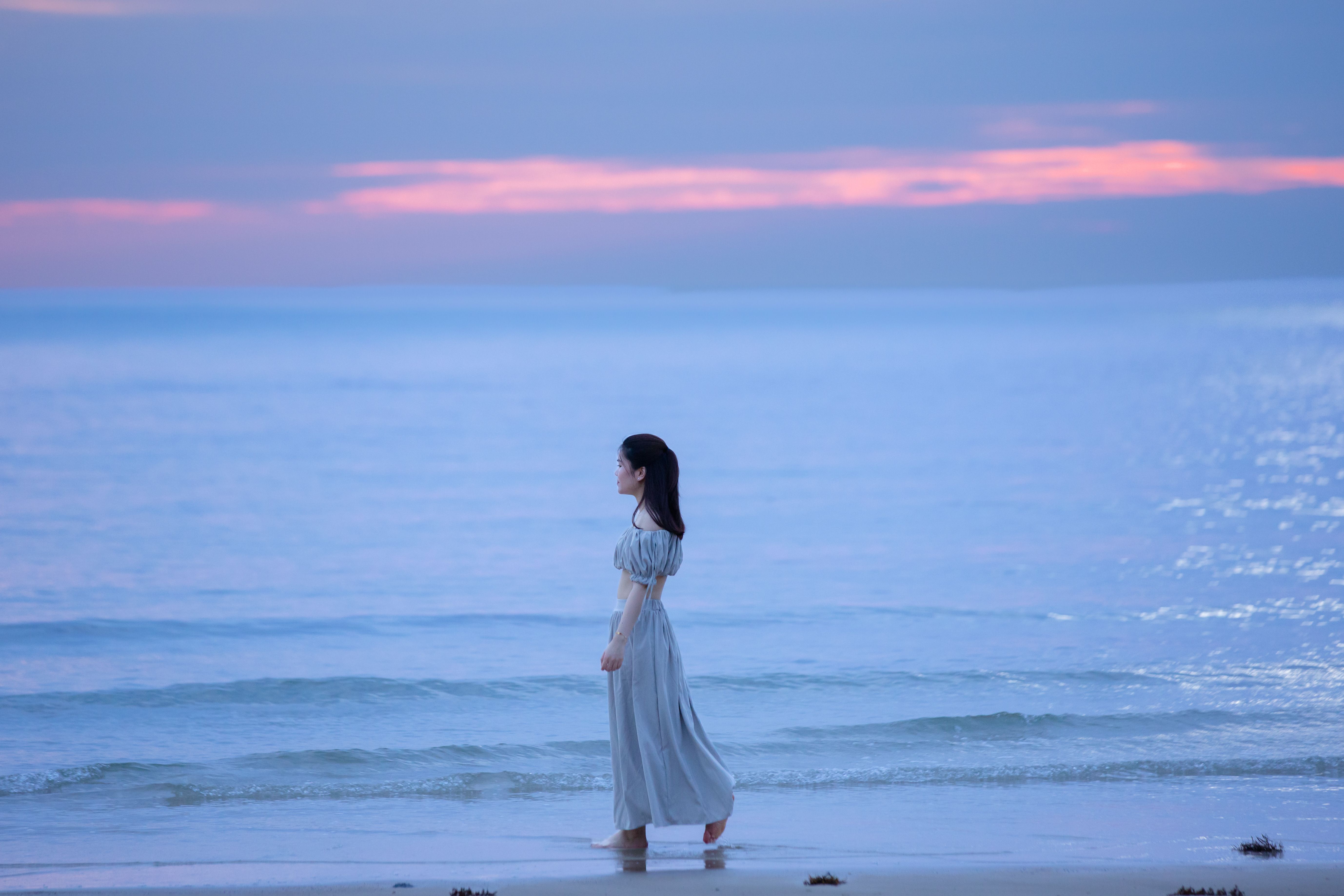 Woman gazing at serene ocean during twilight · Free Stock Photo
