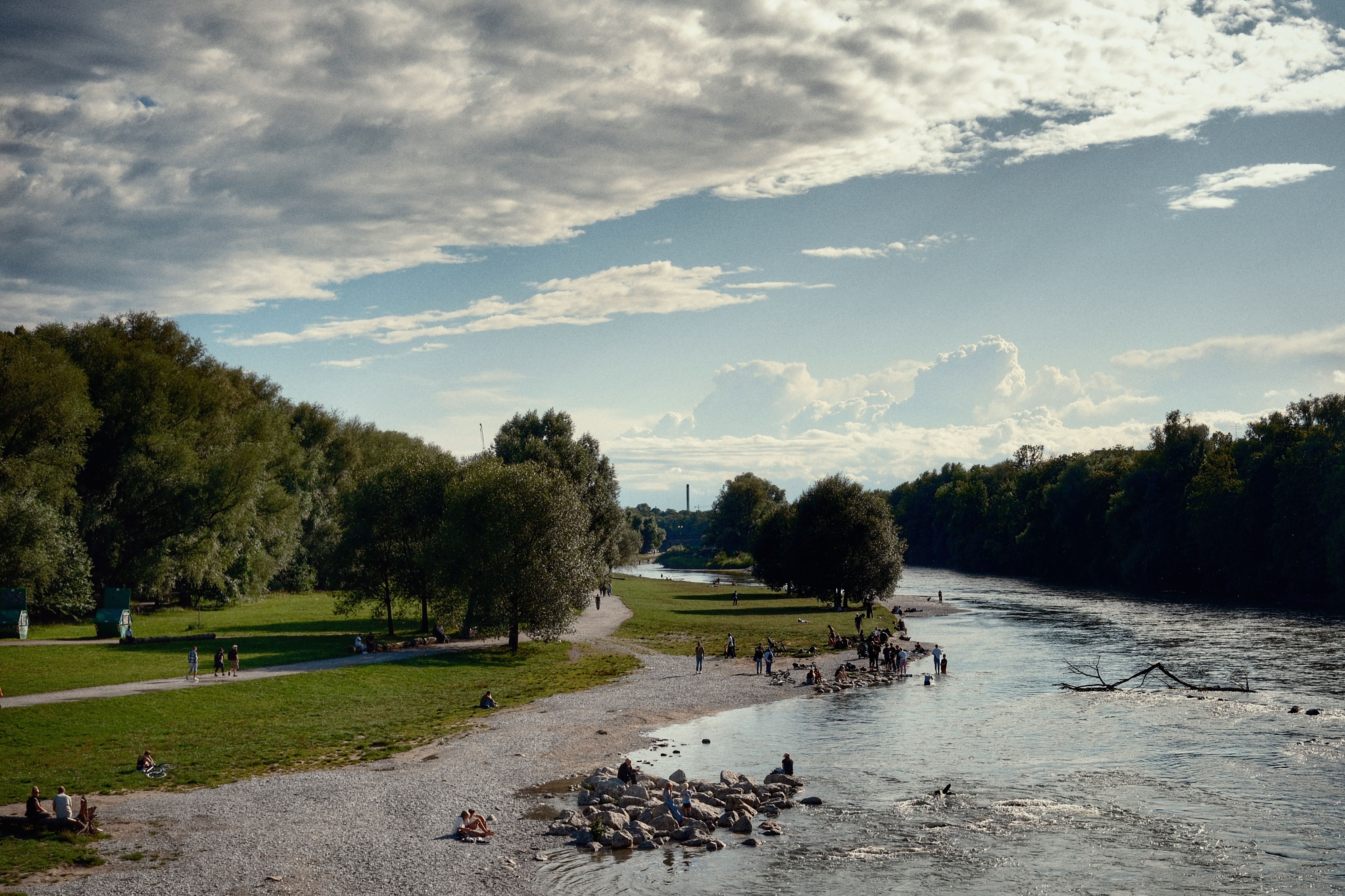 Scenic Riverside Park with People Relaxing · Free Stock Photo