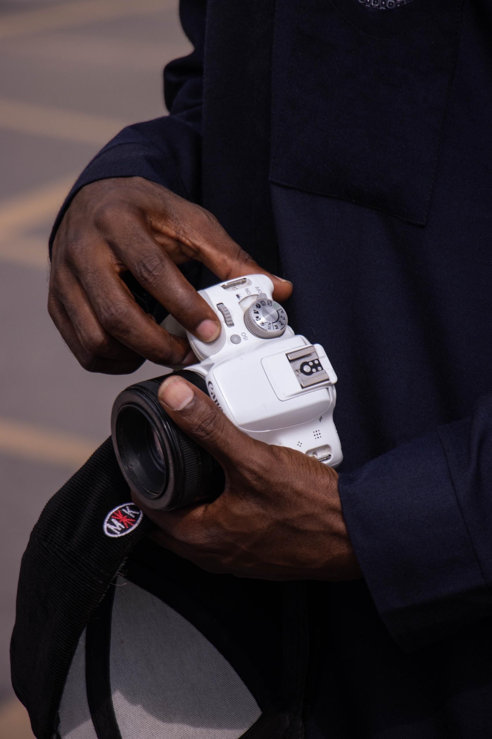 Man Adjusting White Camera Outdoors · Free Stock Photo