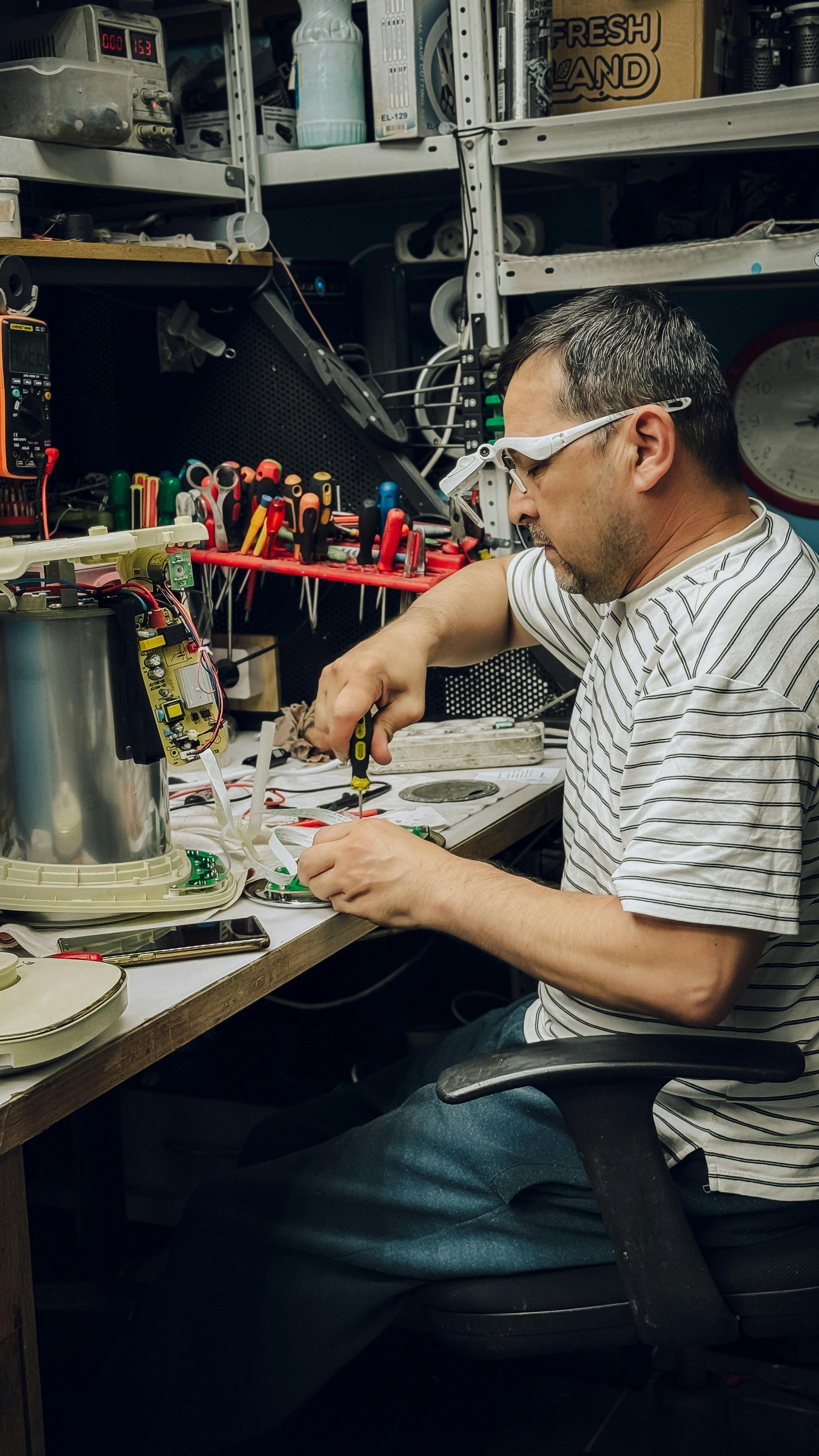 Electrician repairing device in workshop setting · Free Stock Photo