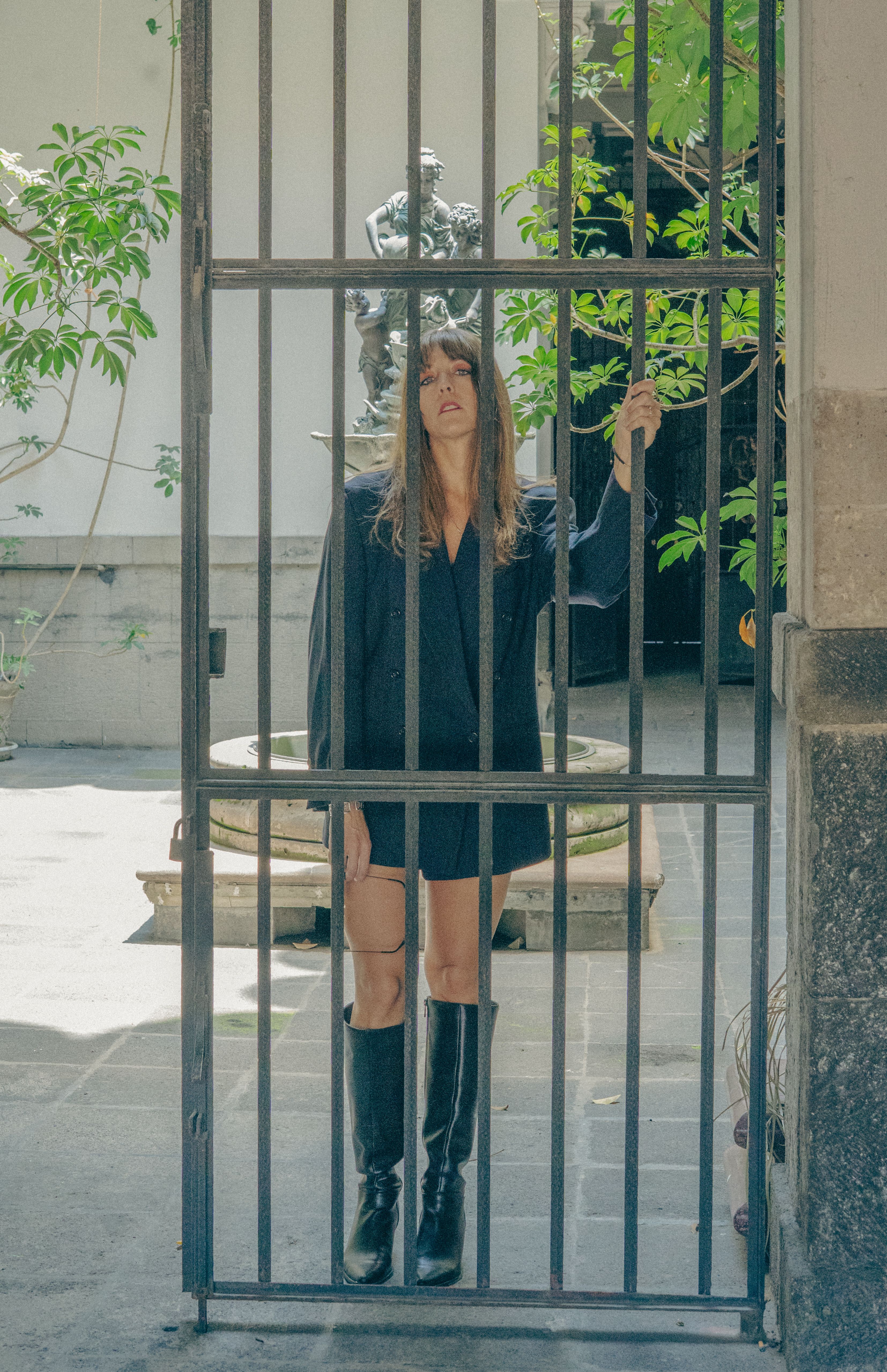 Woman in Courtyard Behind Metal Gate · Free Stock Photo