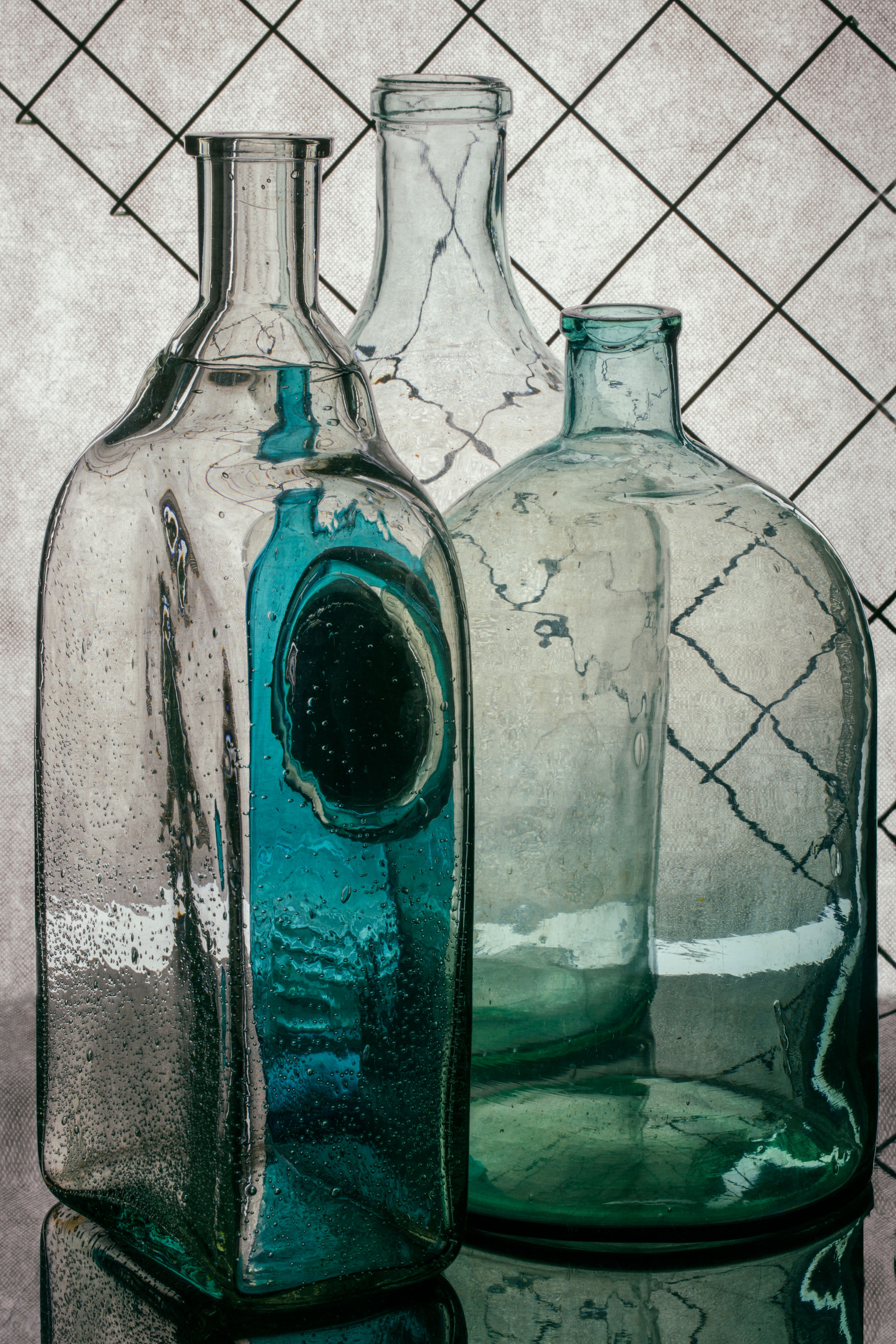 Vintage Glass Bottles on Reflective Surface · Free Stock Photo